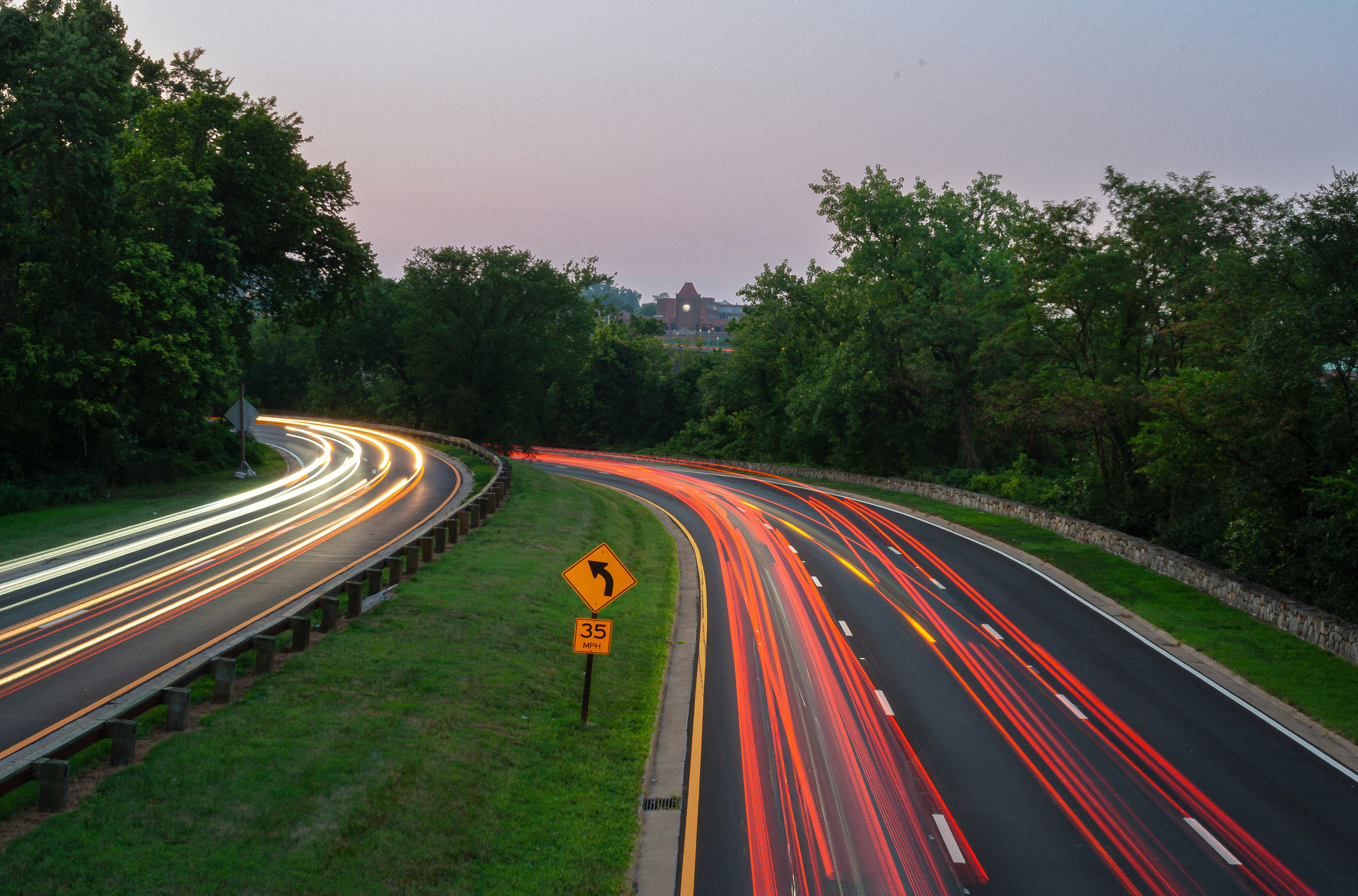 Light trails from cars on a winding highway at twilight.