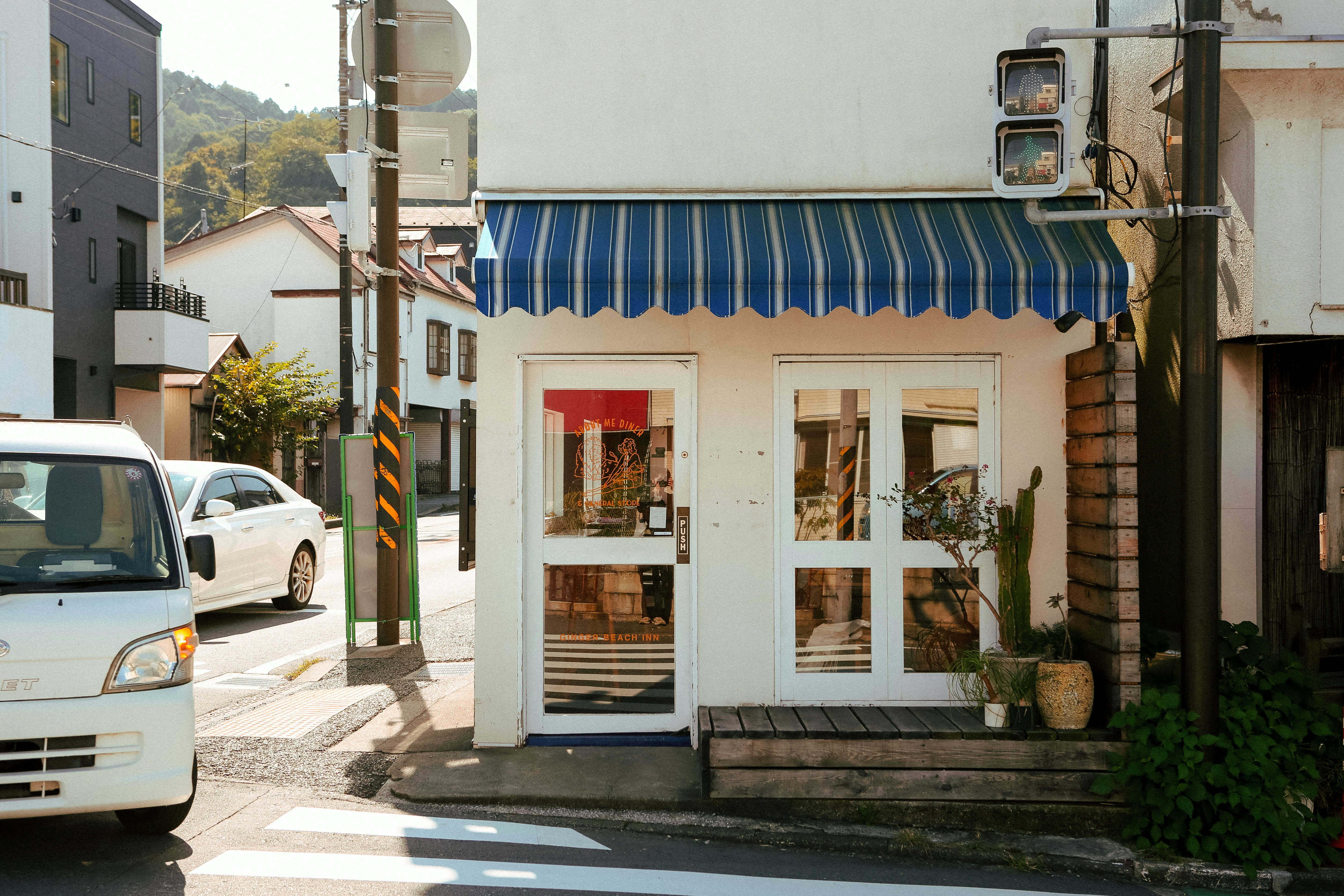 Blue-striped awning over a sunny storefront on a quiet street corner