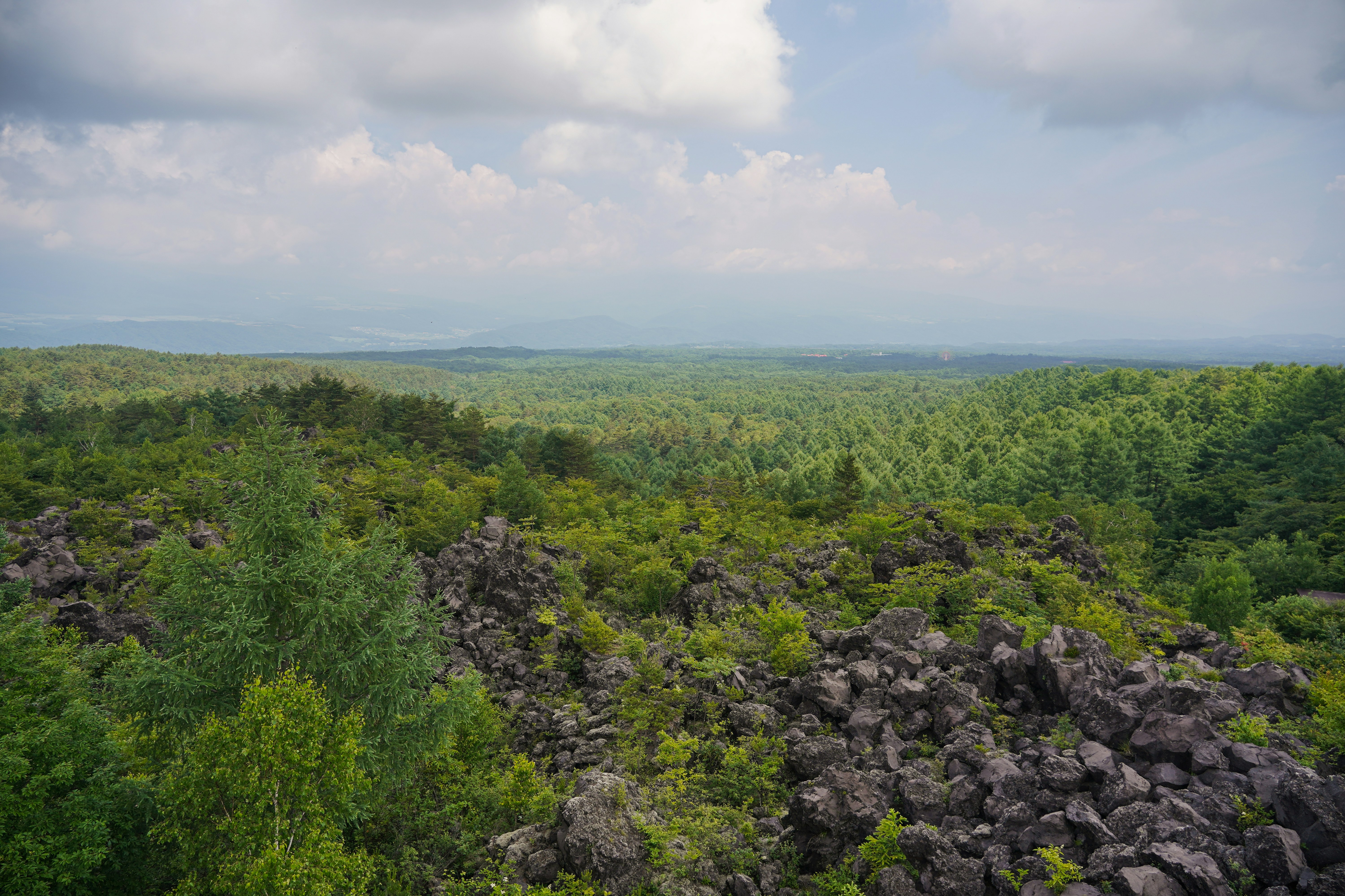 Lava rock ridge giving way to distant green plains under a layered sky