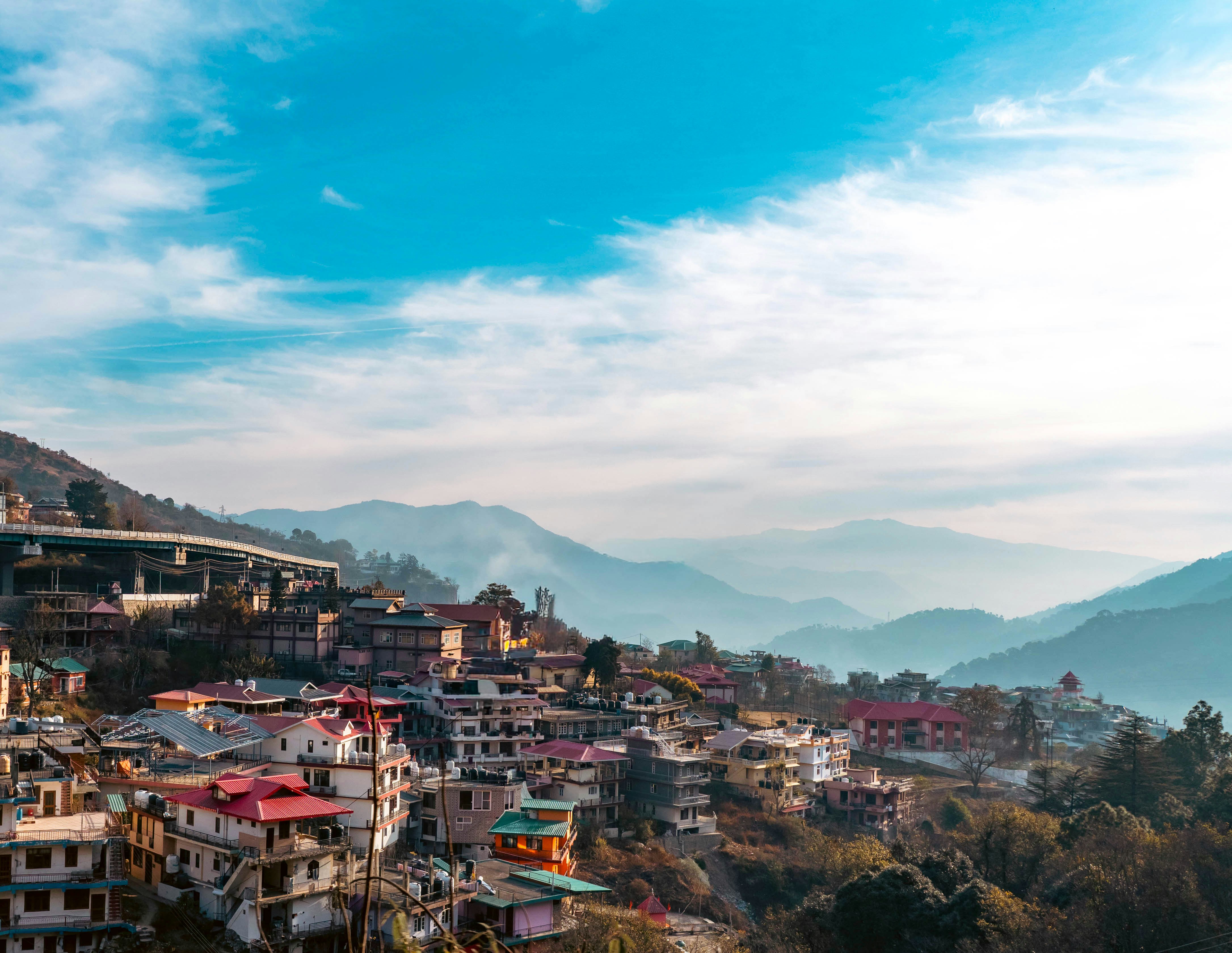Cluster of colorful houses cascading down a hillside under a clear blue sky, with distant mountains fading into the horizon.