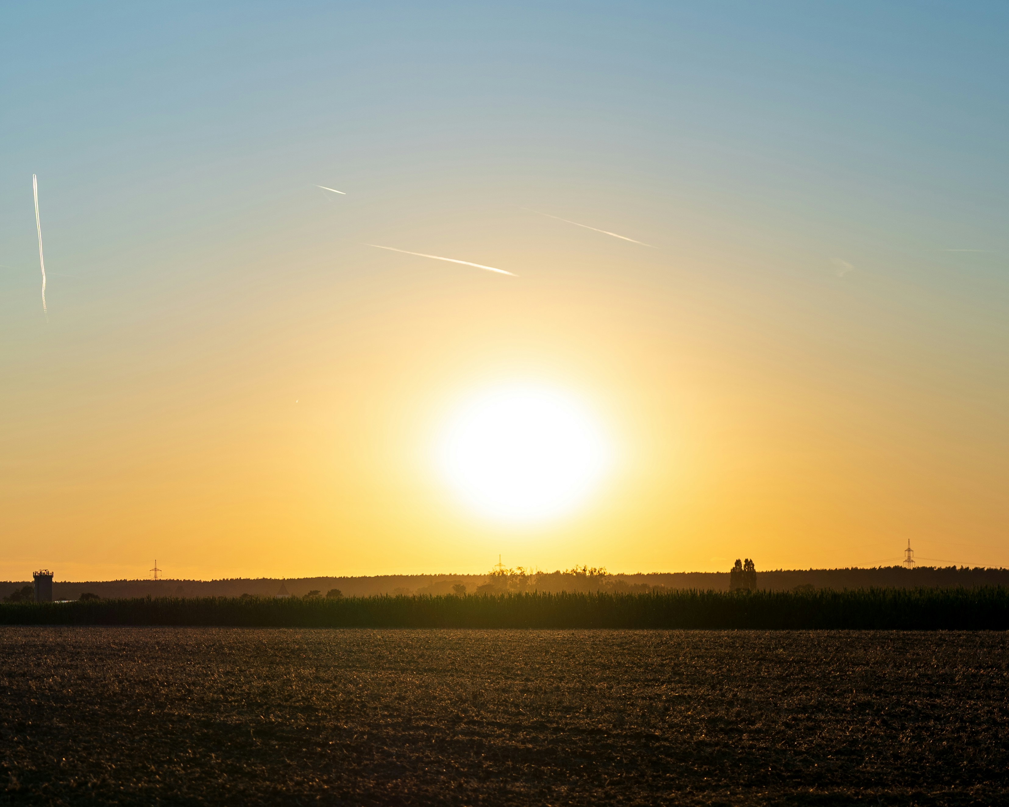 Golden sunset over a vast, dark agricultural field.