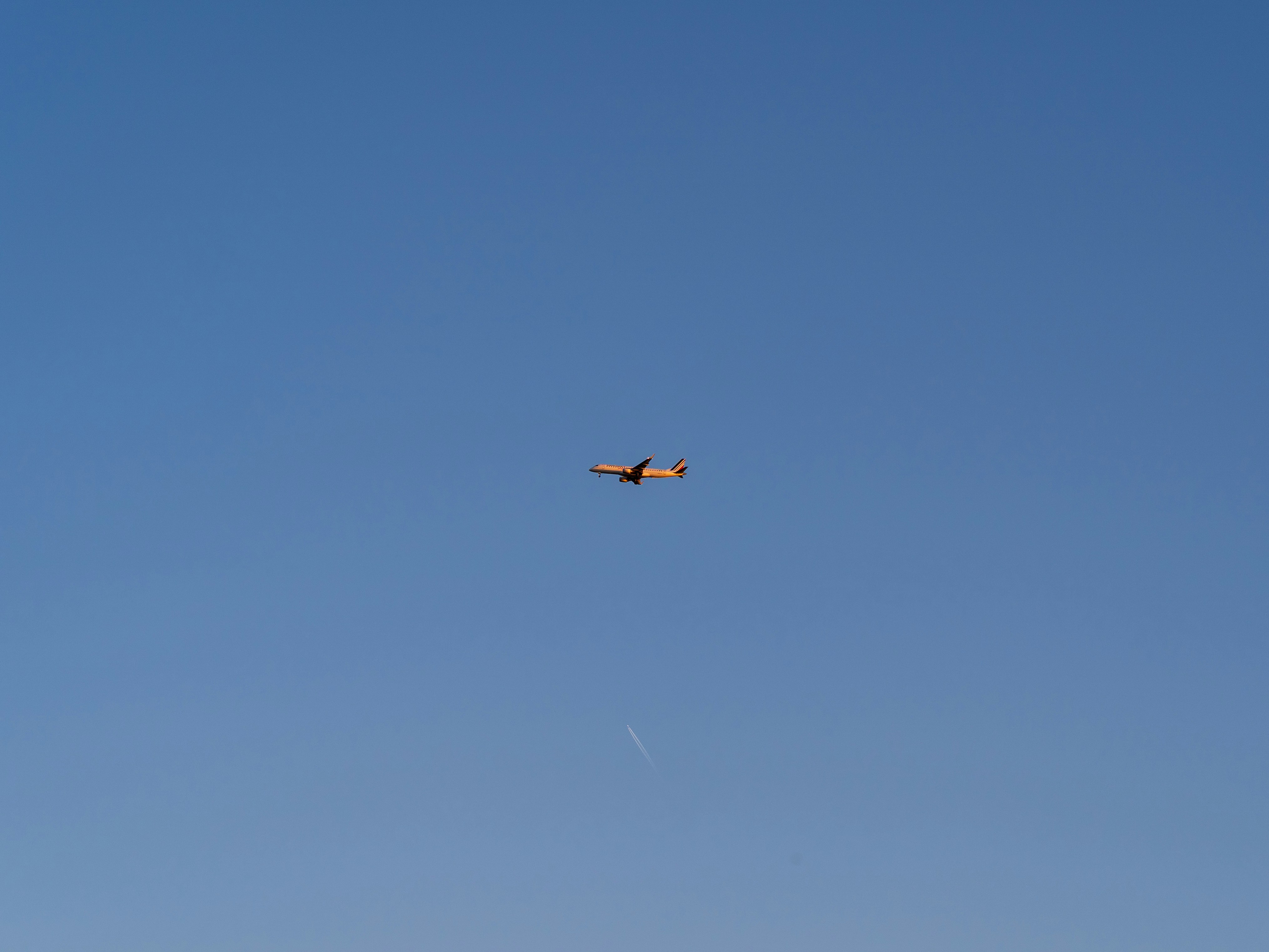 Minimalist Skyflight: A Solo Airplane Crossing a Clear Blue Expanse
