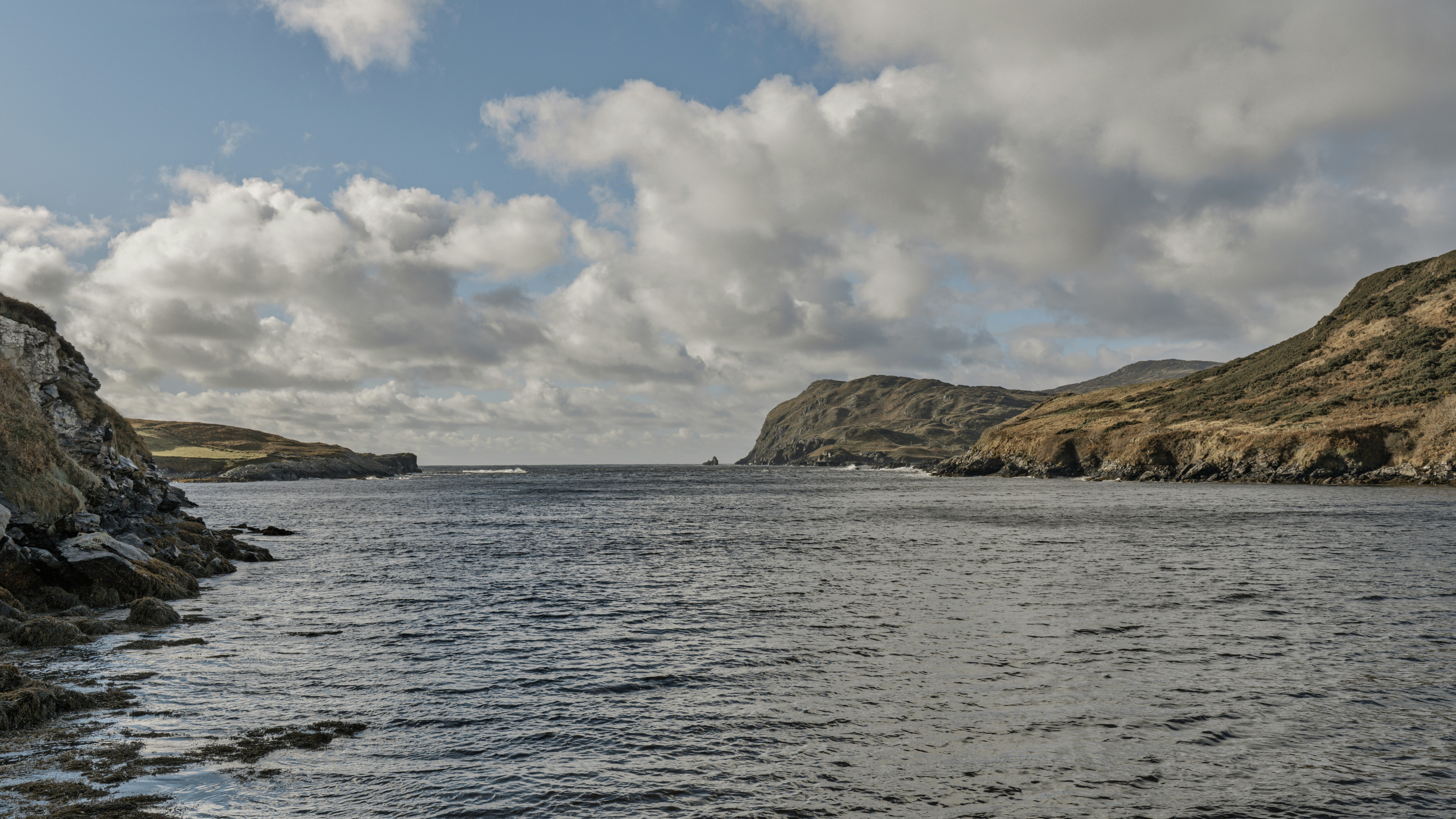 Coastal Convergence: Sunlit Rocks Framing a Quiet Sea