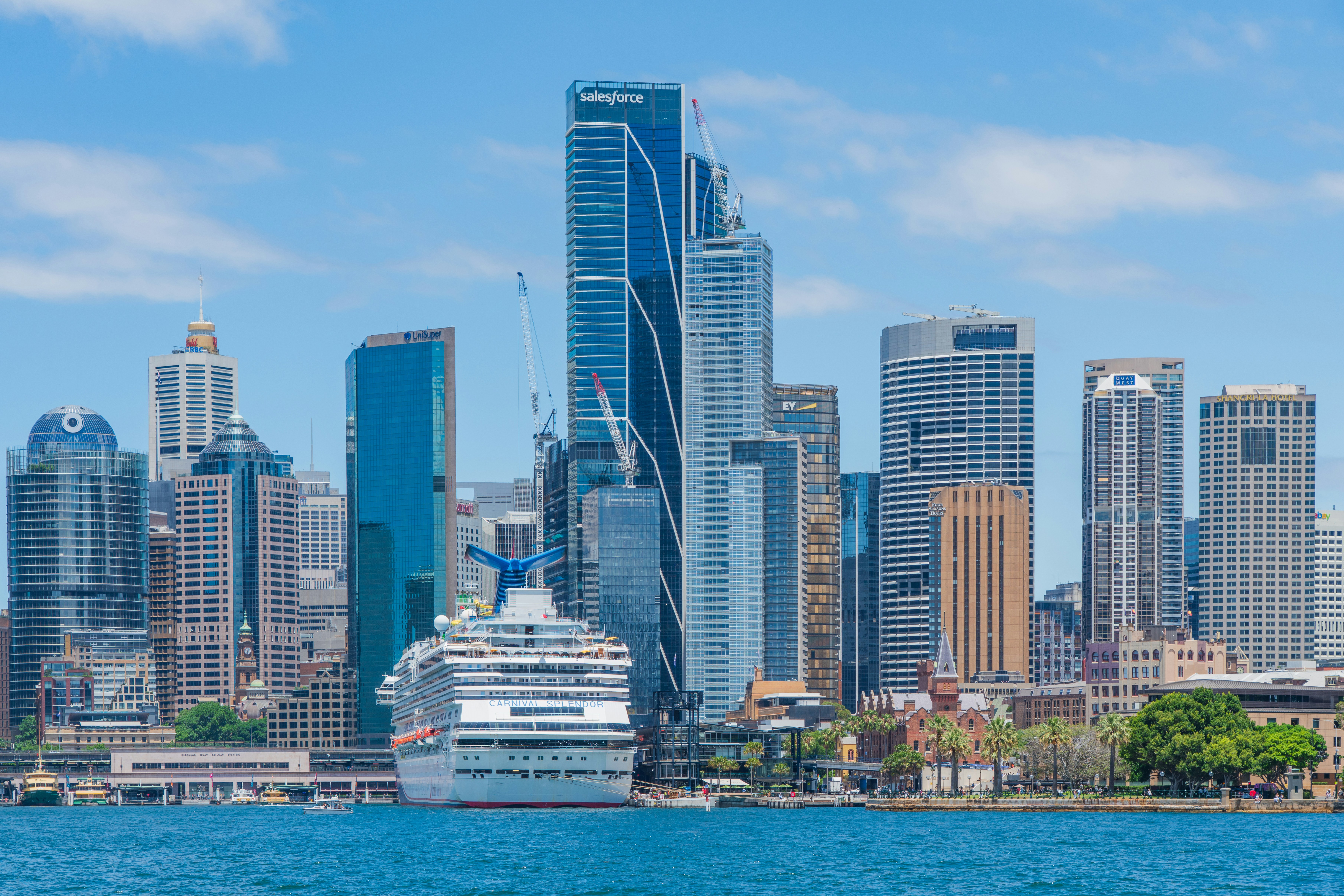 Cruise ship docked in front of a modern city skyline.