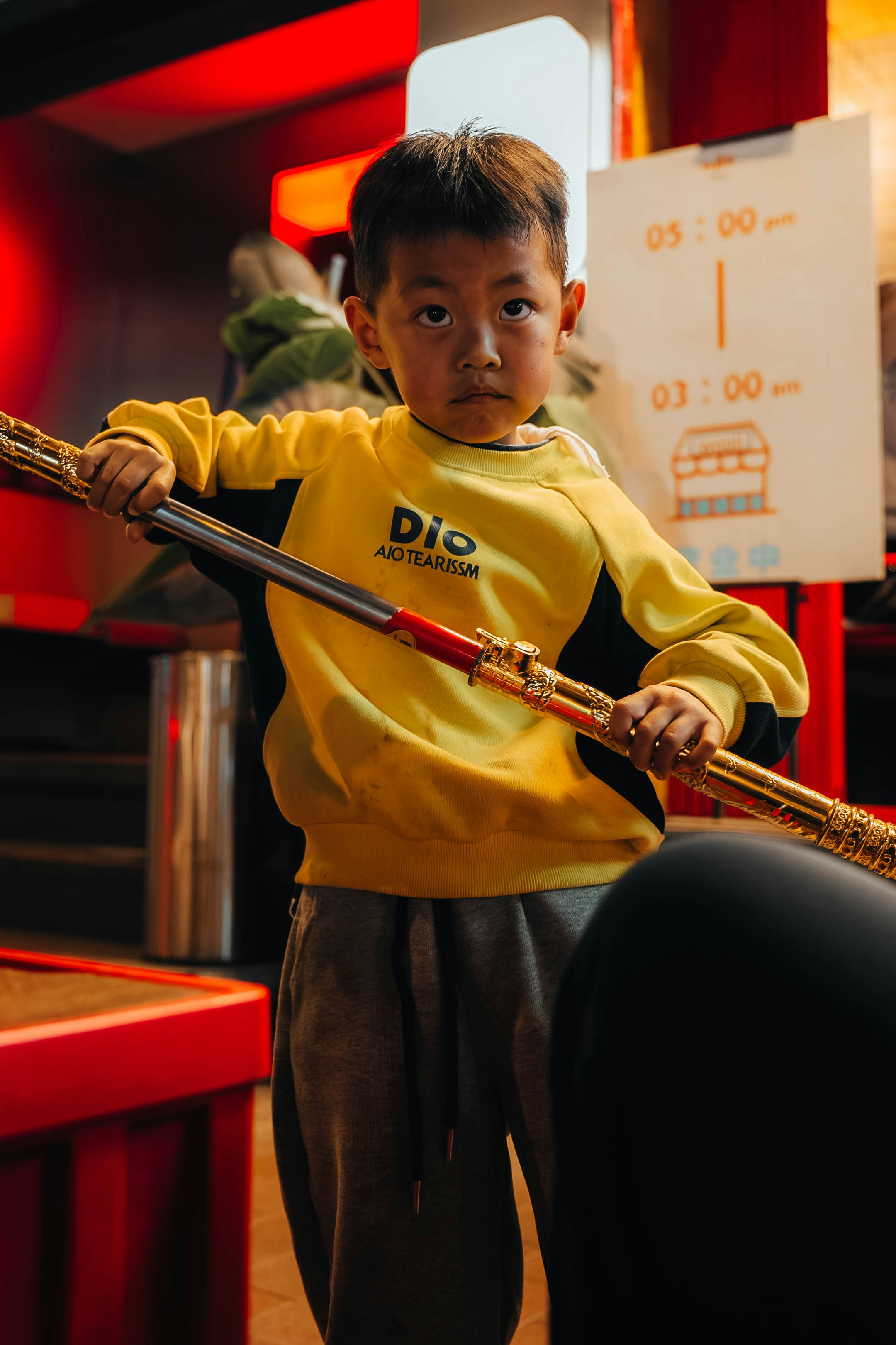 Child with golden baton under red lights in a vibrant indoor scene