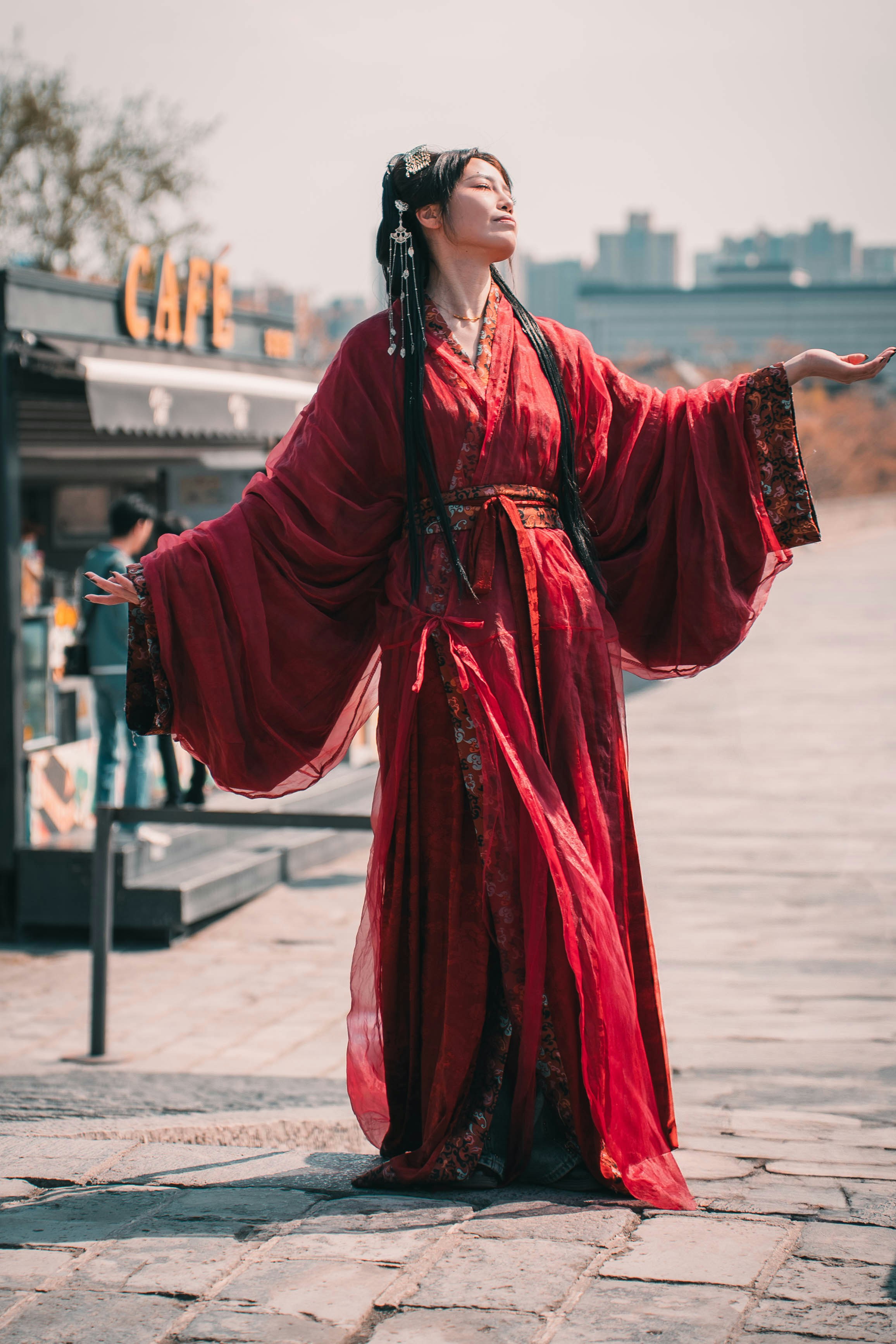 Crimson Robe, Open Arms: A Moment of Poise in the Plaza