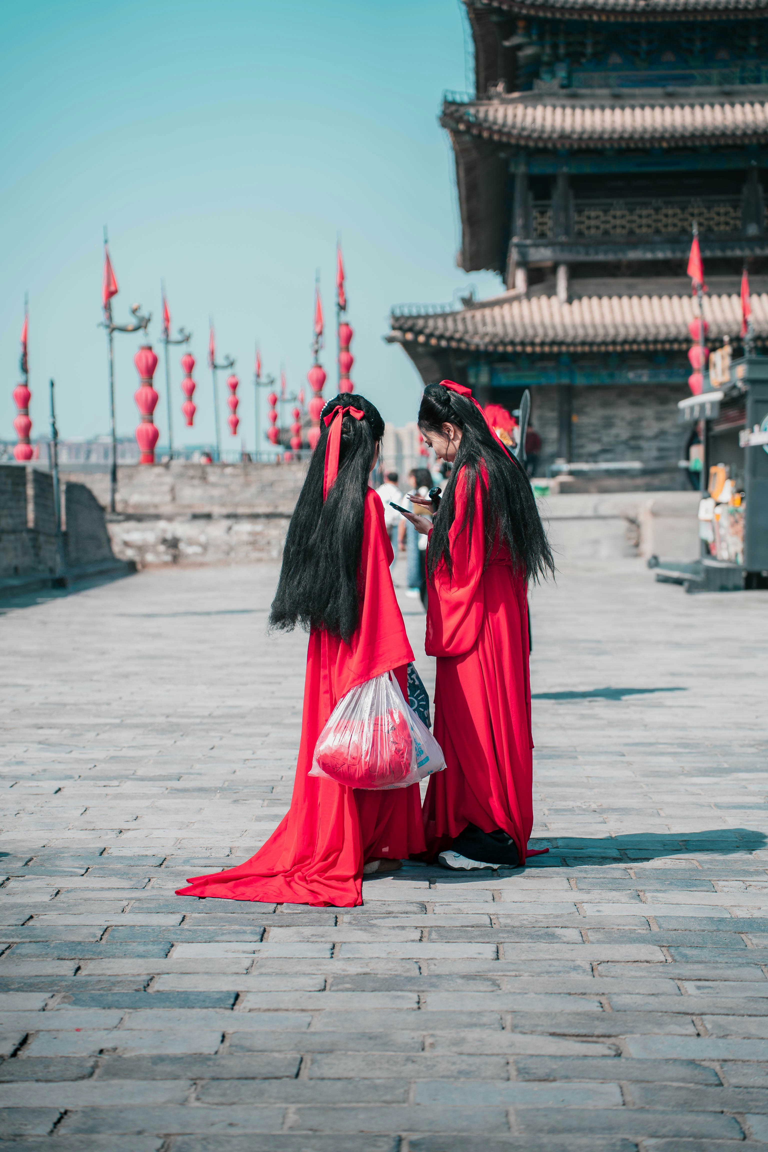 Red Robes at the Gate: Two Women in Traditional Attire at a Historic Terrace