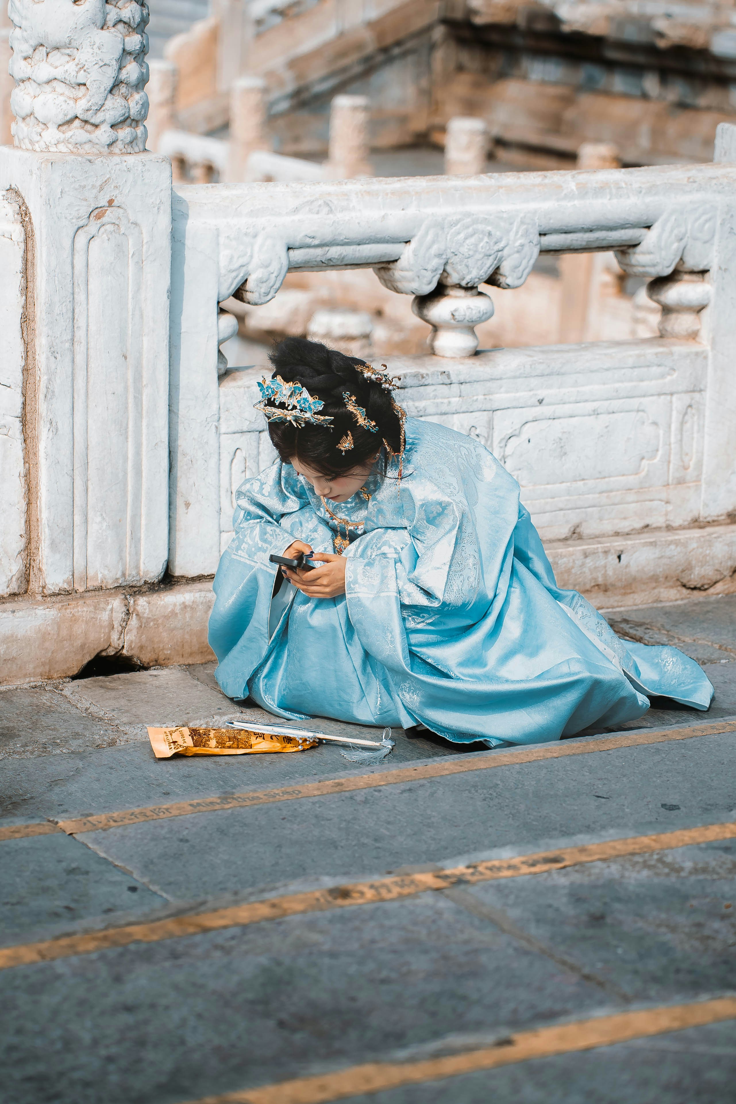 Blue-sashed Child of the Terrace: Quiet Moment with a Glance at a handheld Device