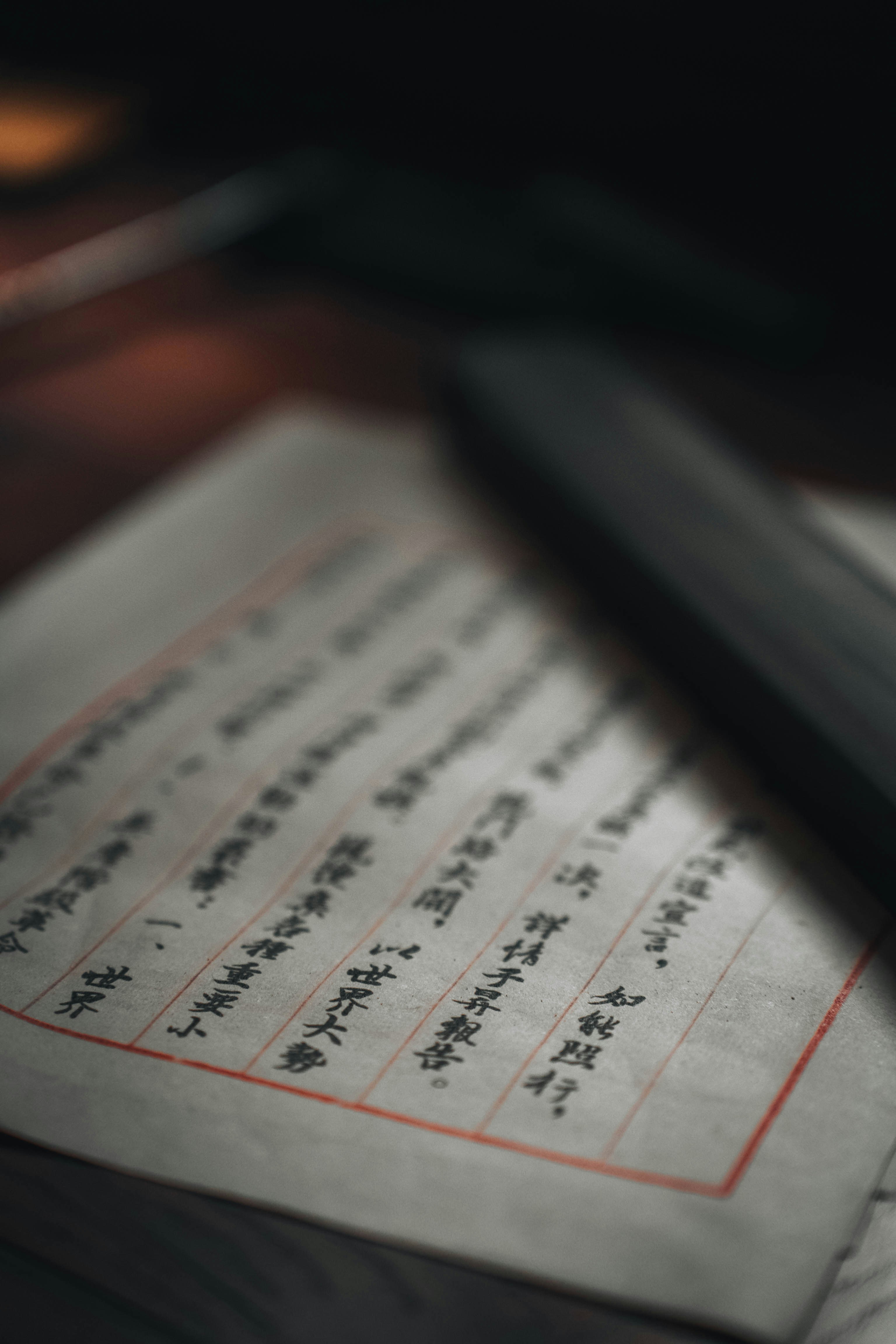 Redacted Script in Focus: A Dimly Lit Page and Pen in a Wooden Desk Scene