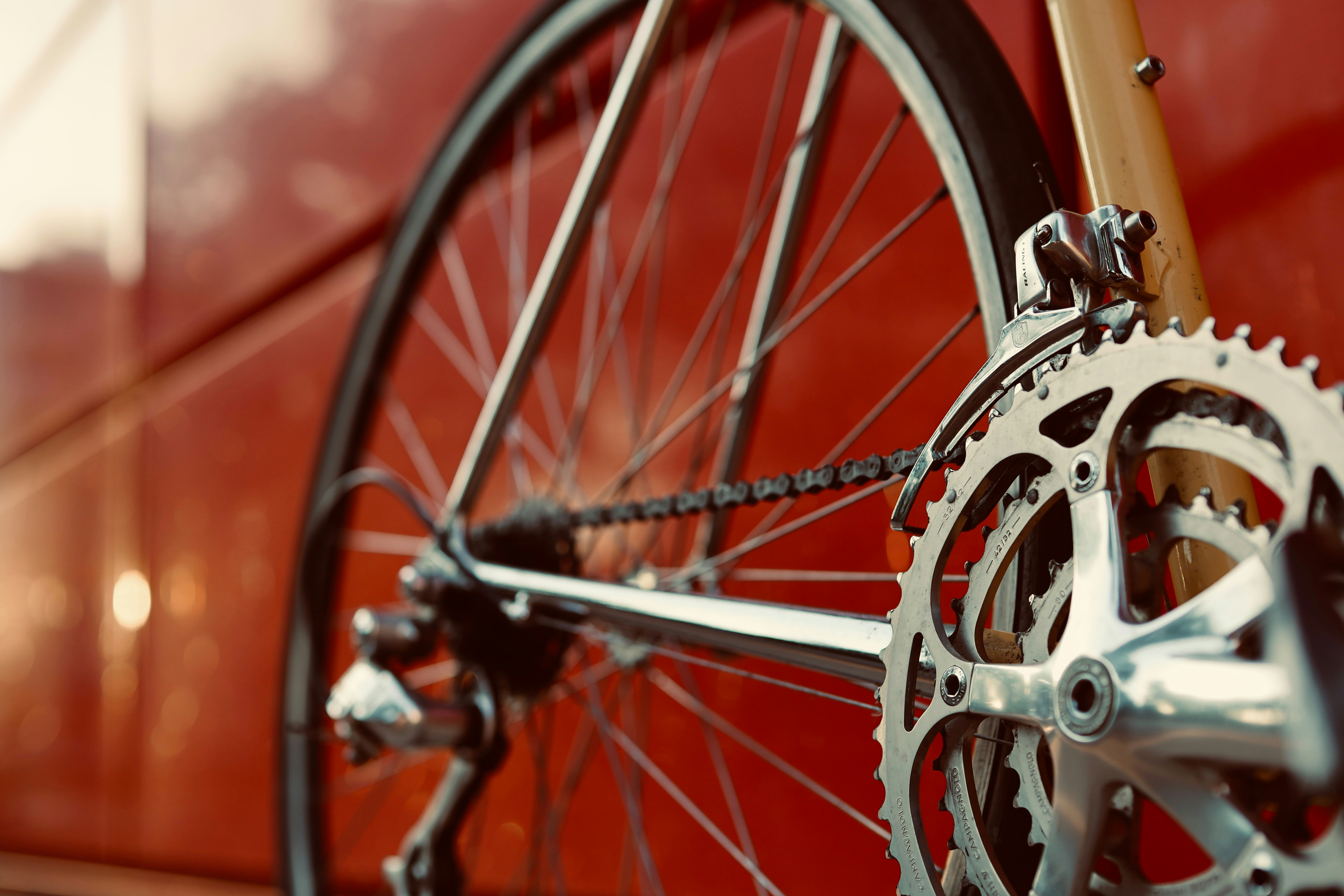 Close-up of a bicycle crankset and chainring in warm automotive-red background