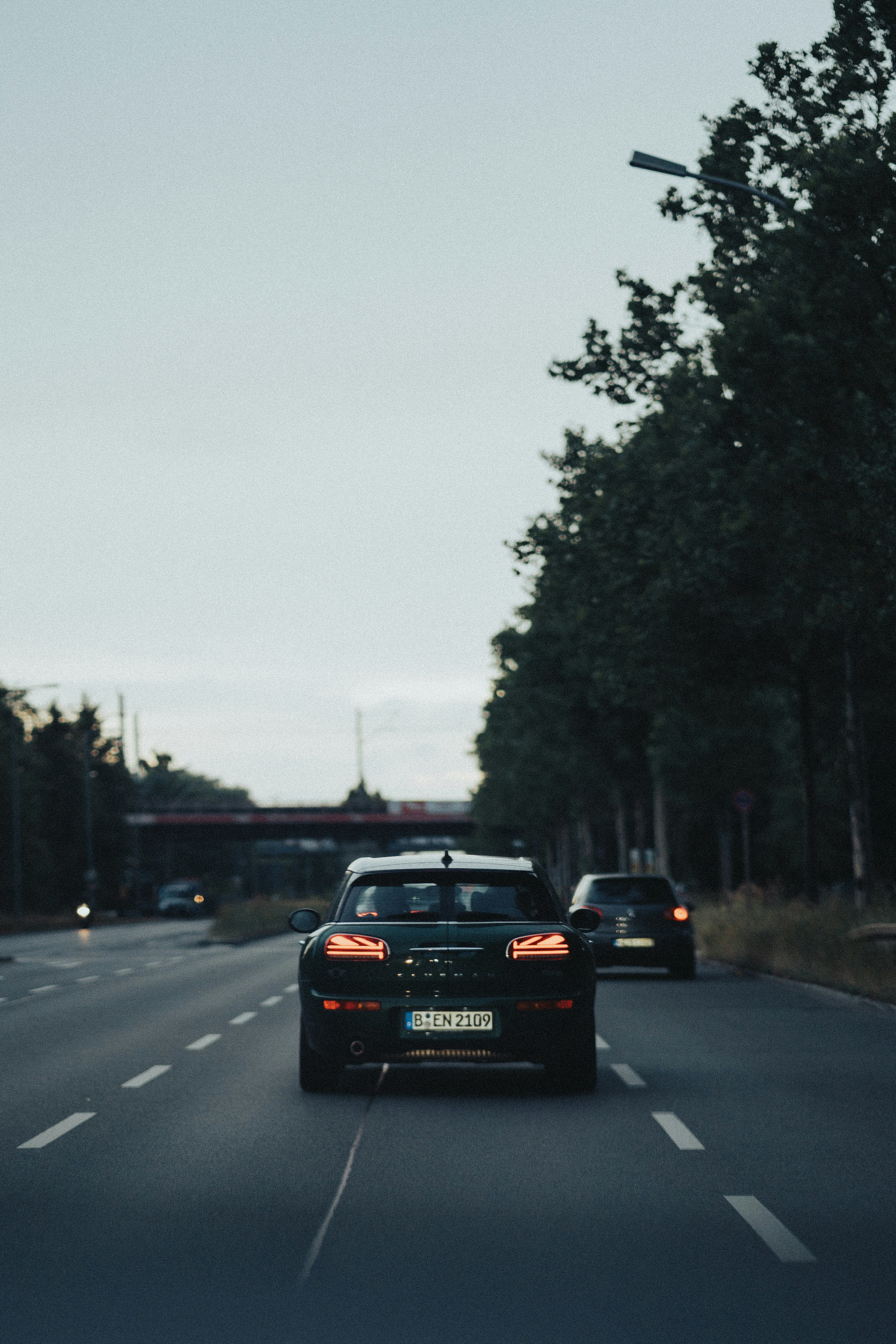 Rear-View Pursuit: A Black Sports Car Traverses a Quiet Evening Highway