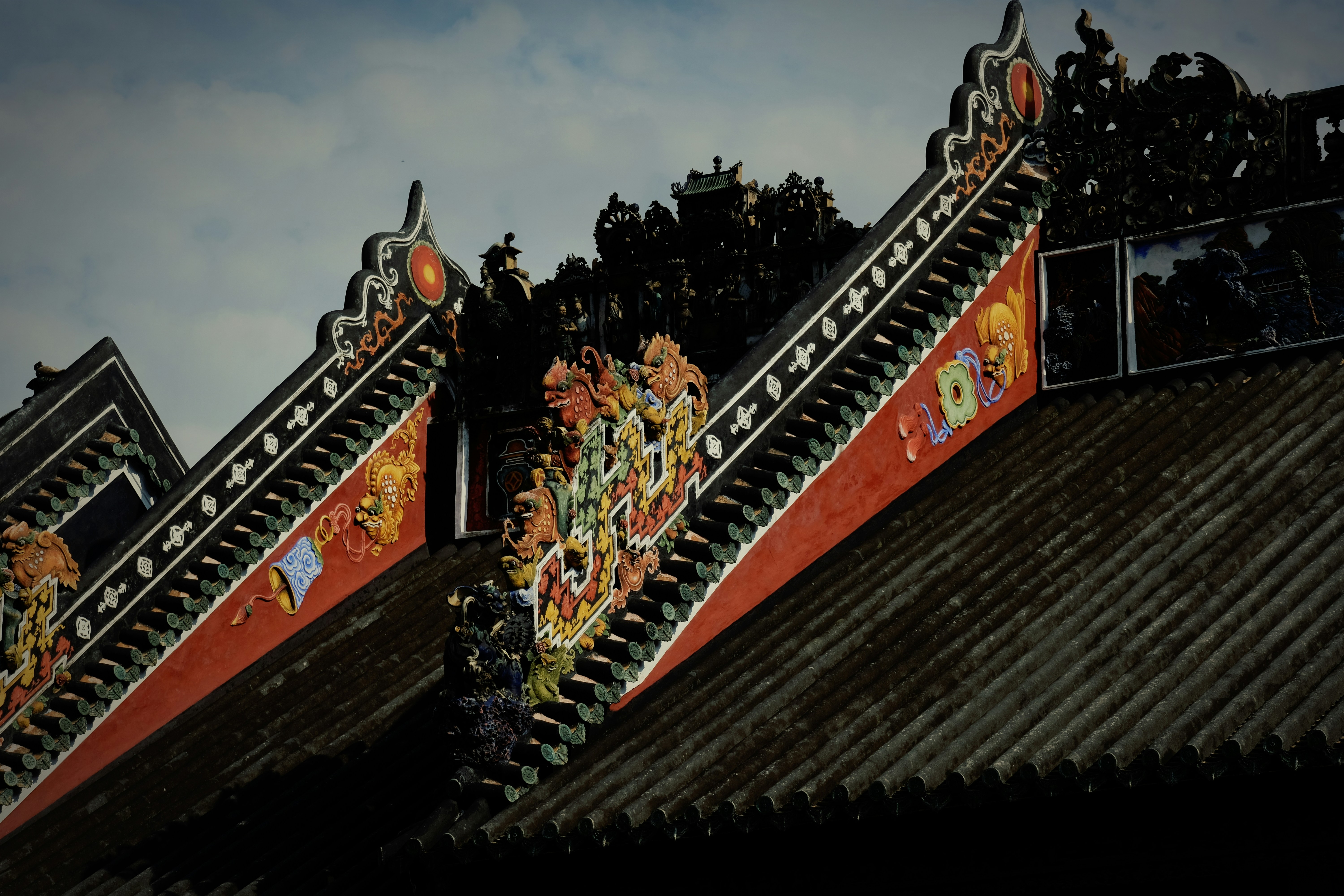 Carved Peaks: Ornate Roof Frieze Over a Darkened Tile Slope