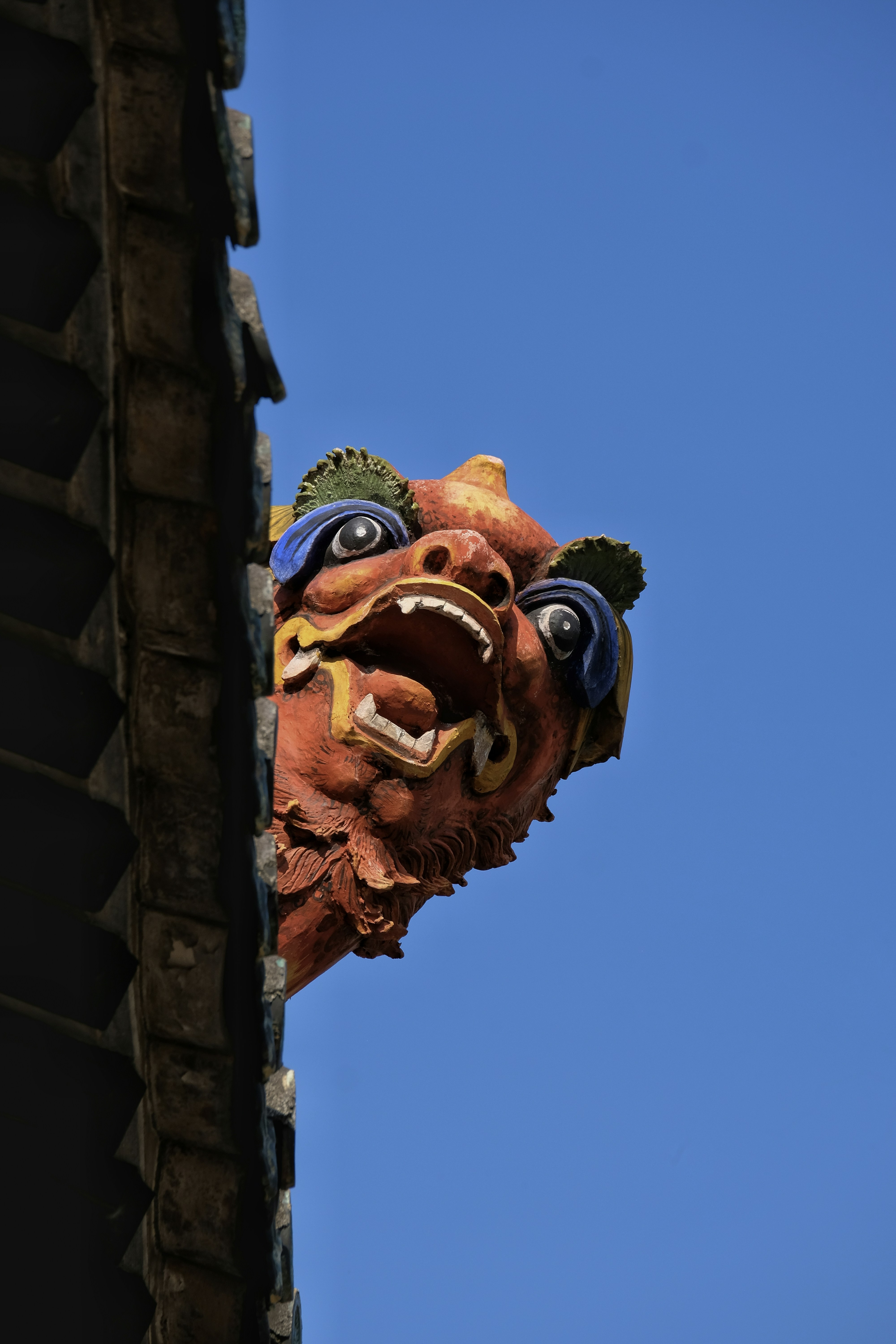 Watcher Above the Tile: A Ceremonial Mask Peers from the Roof