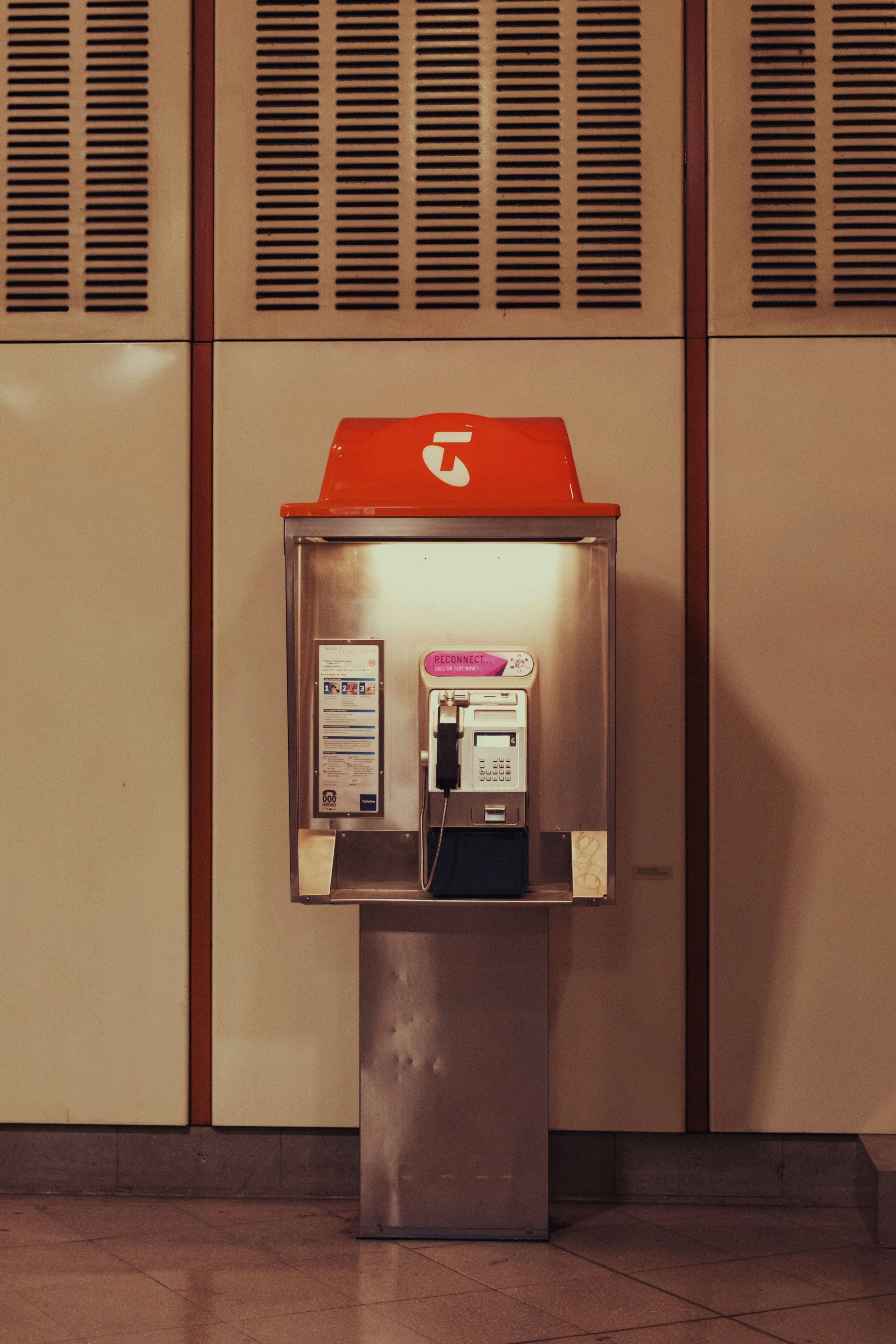 Red Payphone Amid Tall Beige Panels