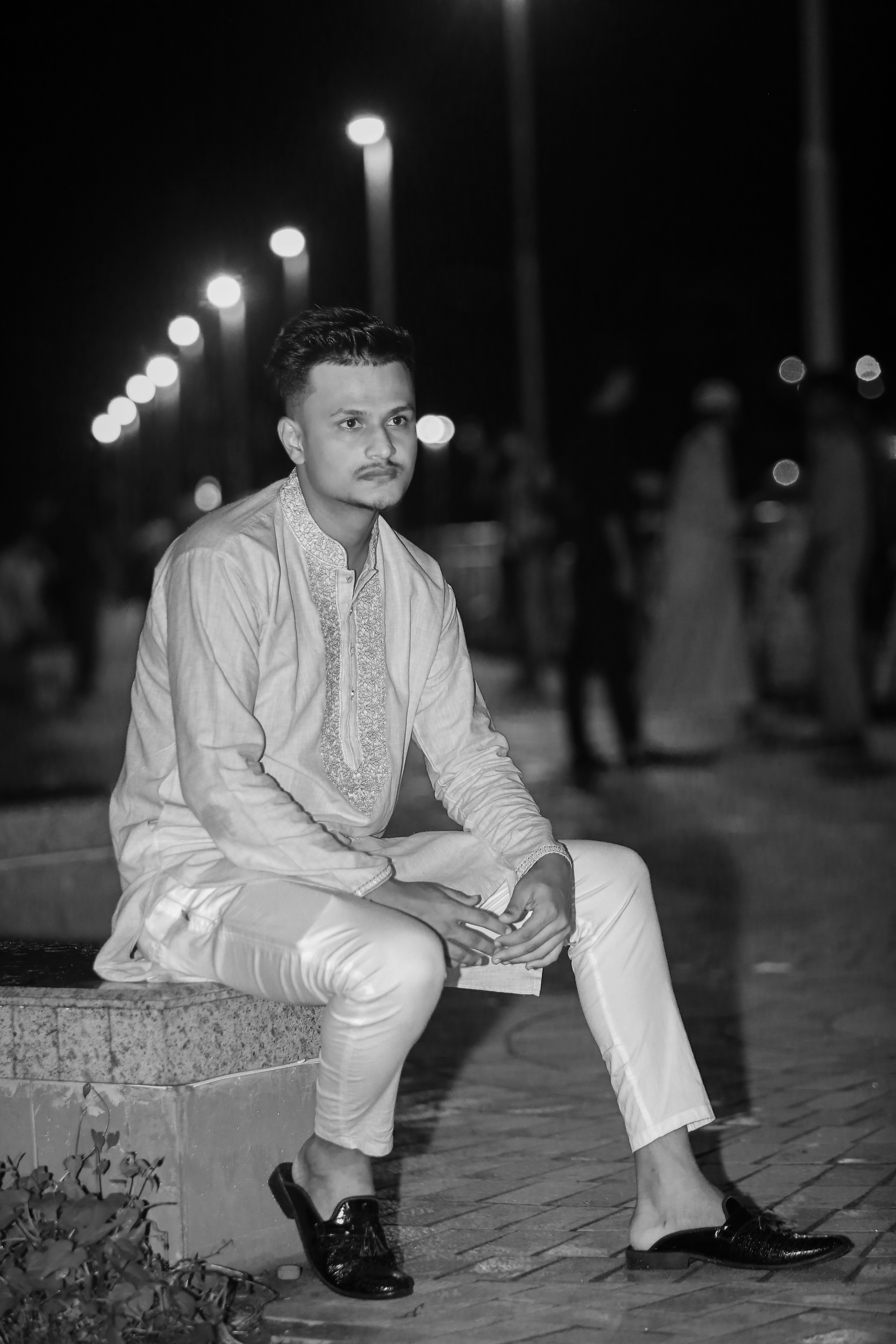Nighttime contemplation: a poised sitter in traditional attire under distant streetlamps