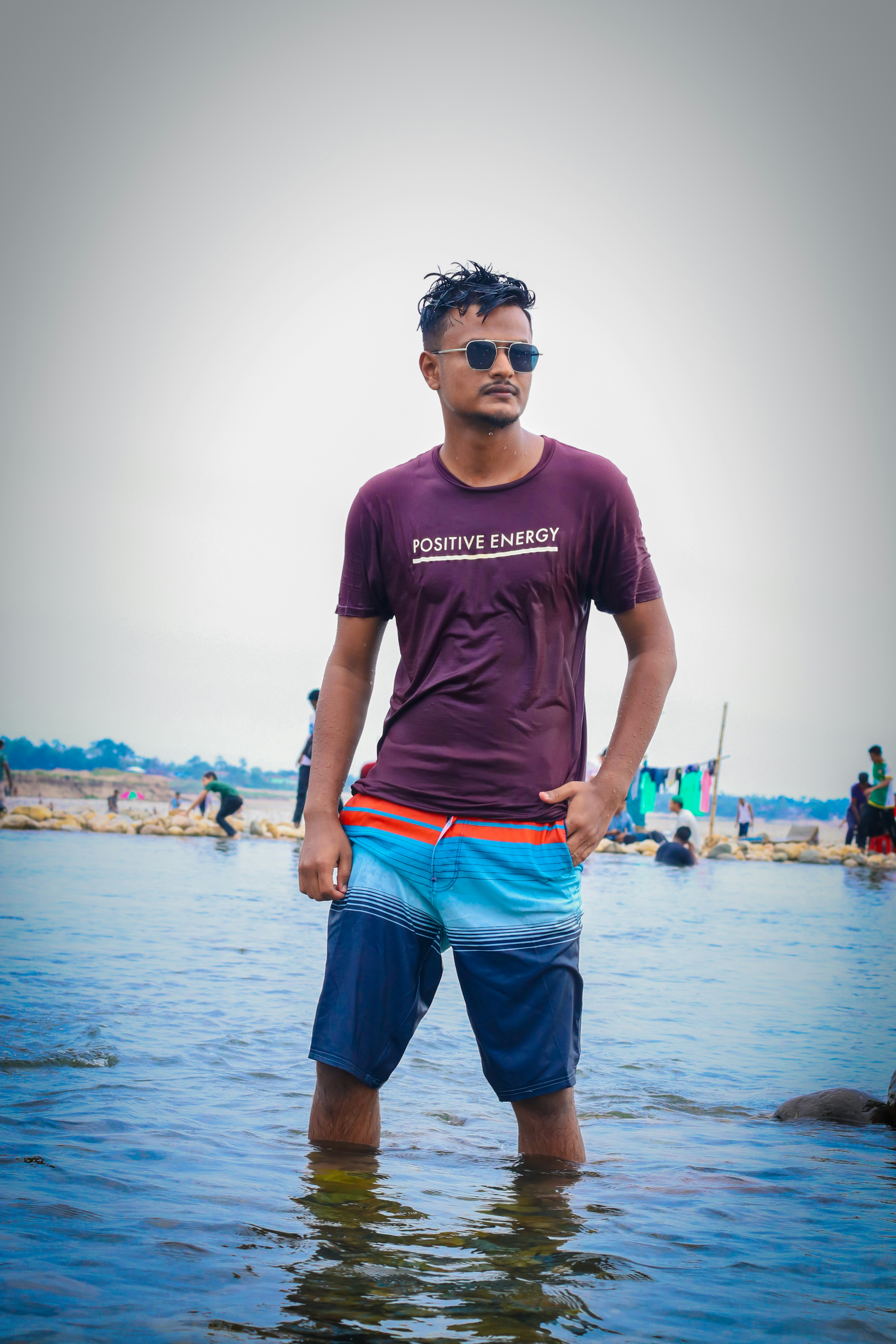Sunlit stance: a beach breaker in maroon and teal stands tall at the shore