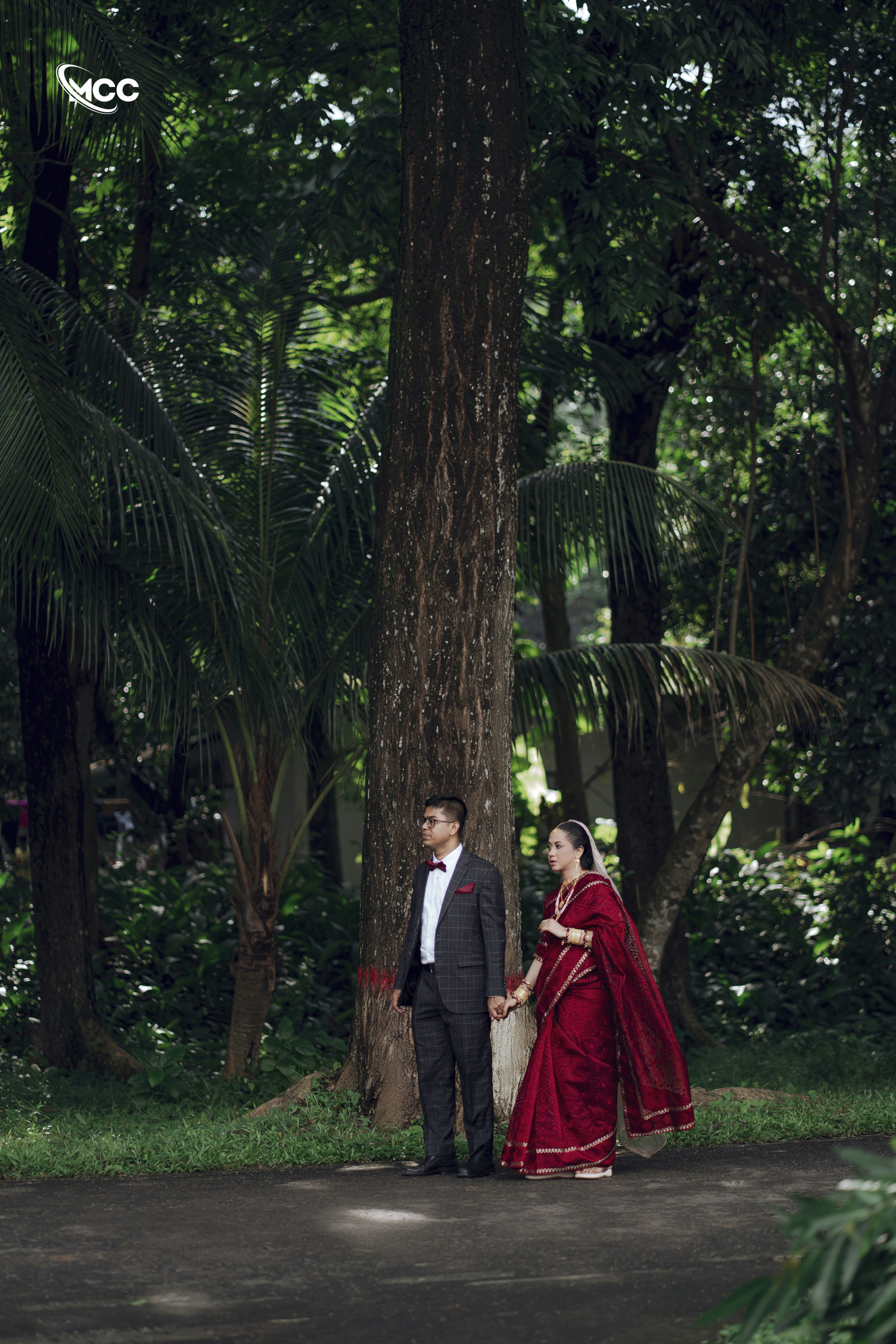 Couple in Elegant Attire Beside a Majestic Tree