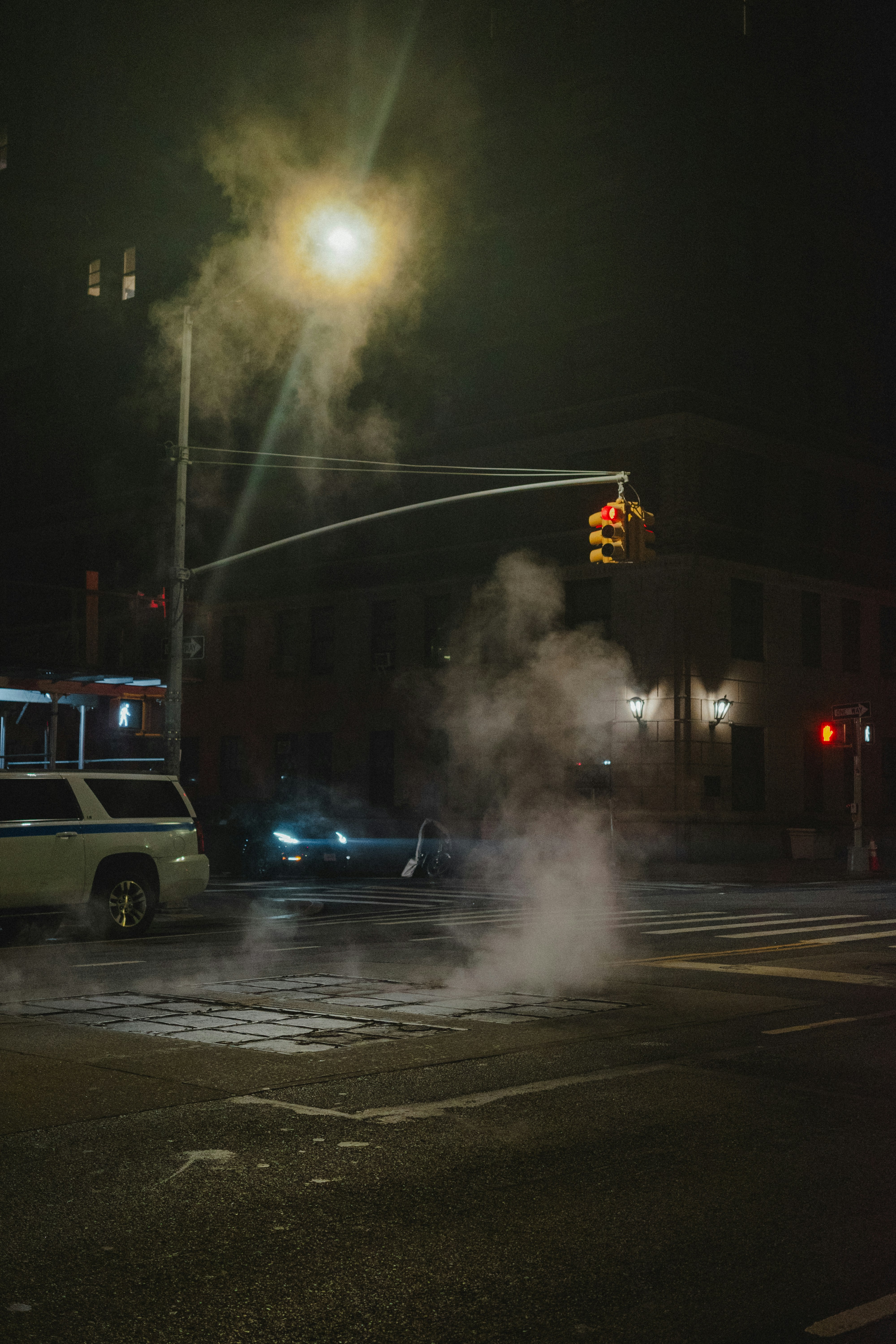 Steam rising from a city street at night.