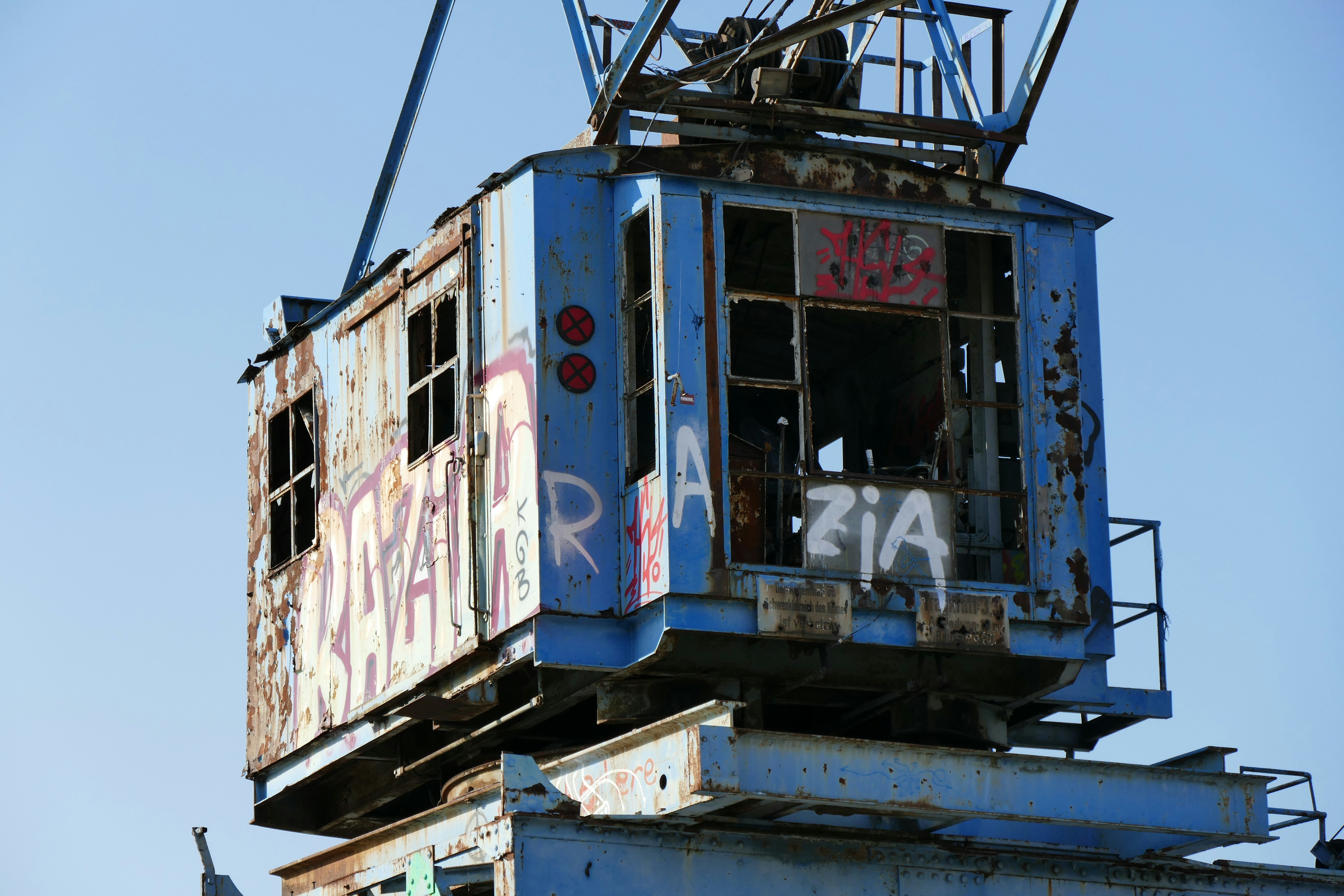 Graffiti-touched Crane Pod: A Rusted Blue Sentinel Overlooking the Sky
