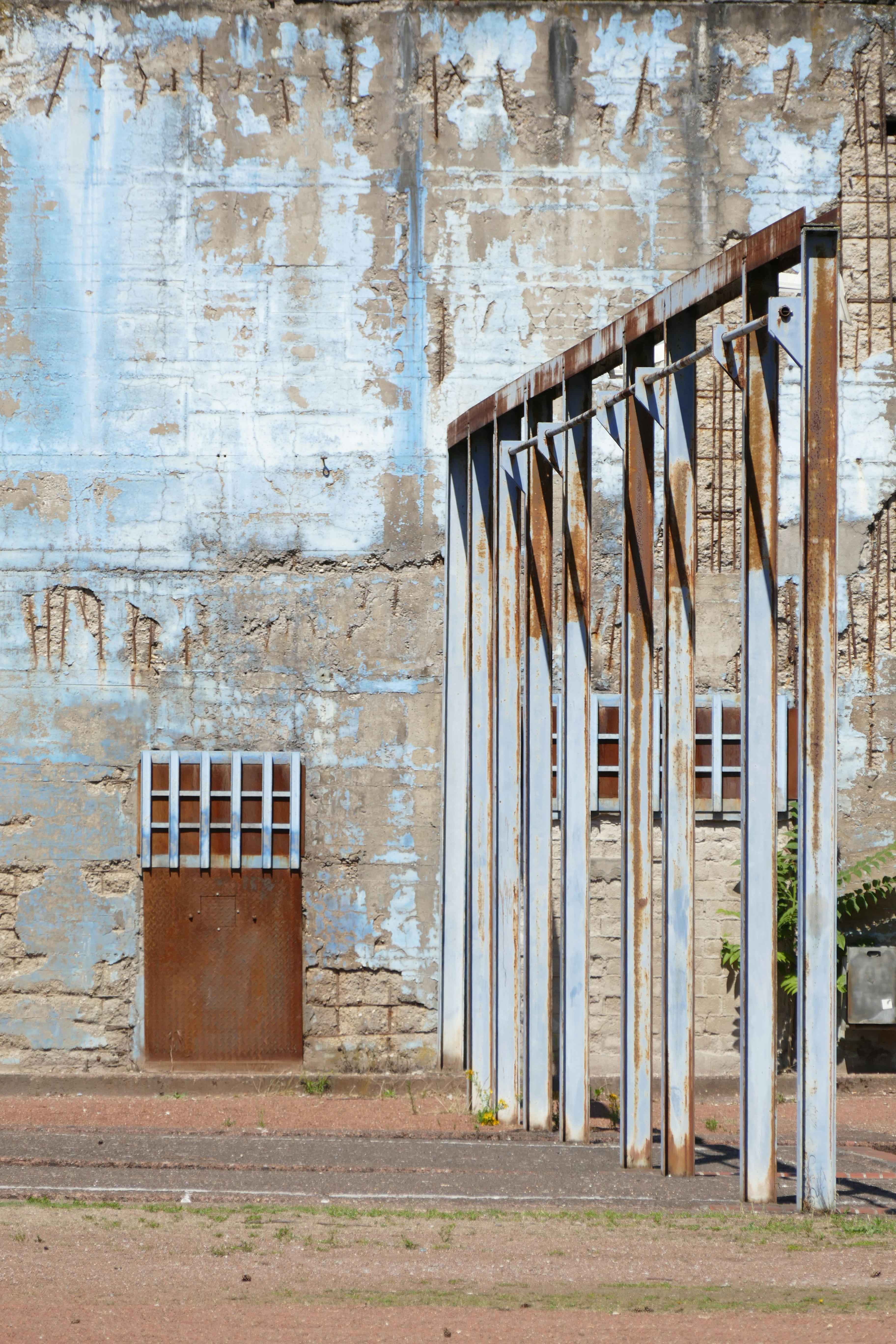 Weathered Steel: Echoes of a Dismantled Arch Beside a Crumbling Wall