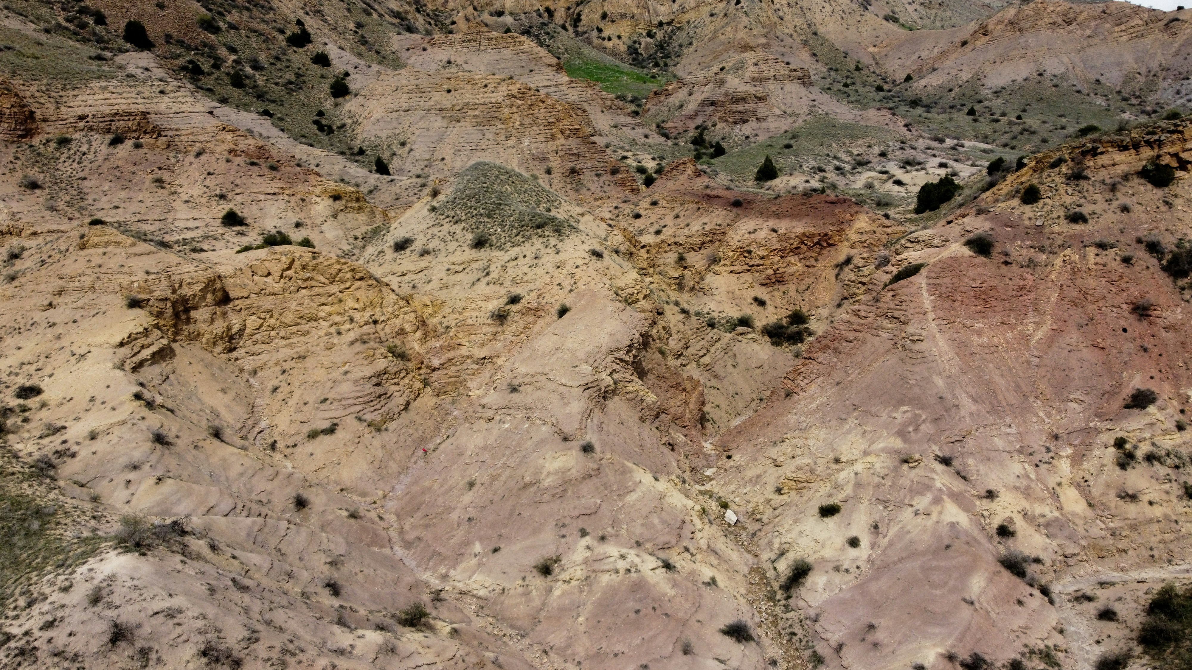 Arid desert mountains with colorful rock formations and sparse bushes