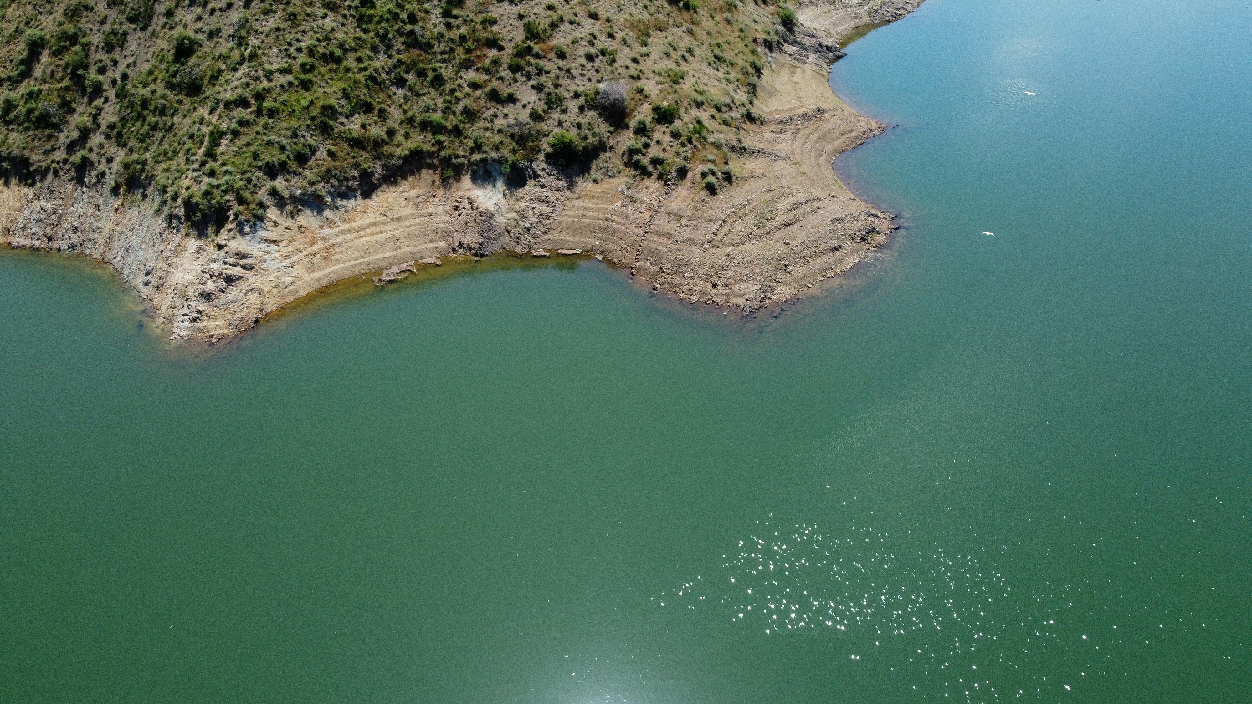 Coastal Inlet from Above: Green Waters Meet Rusted Cliff Edge