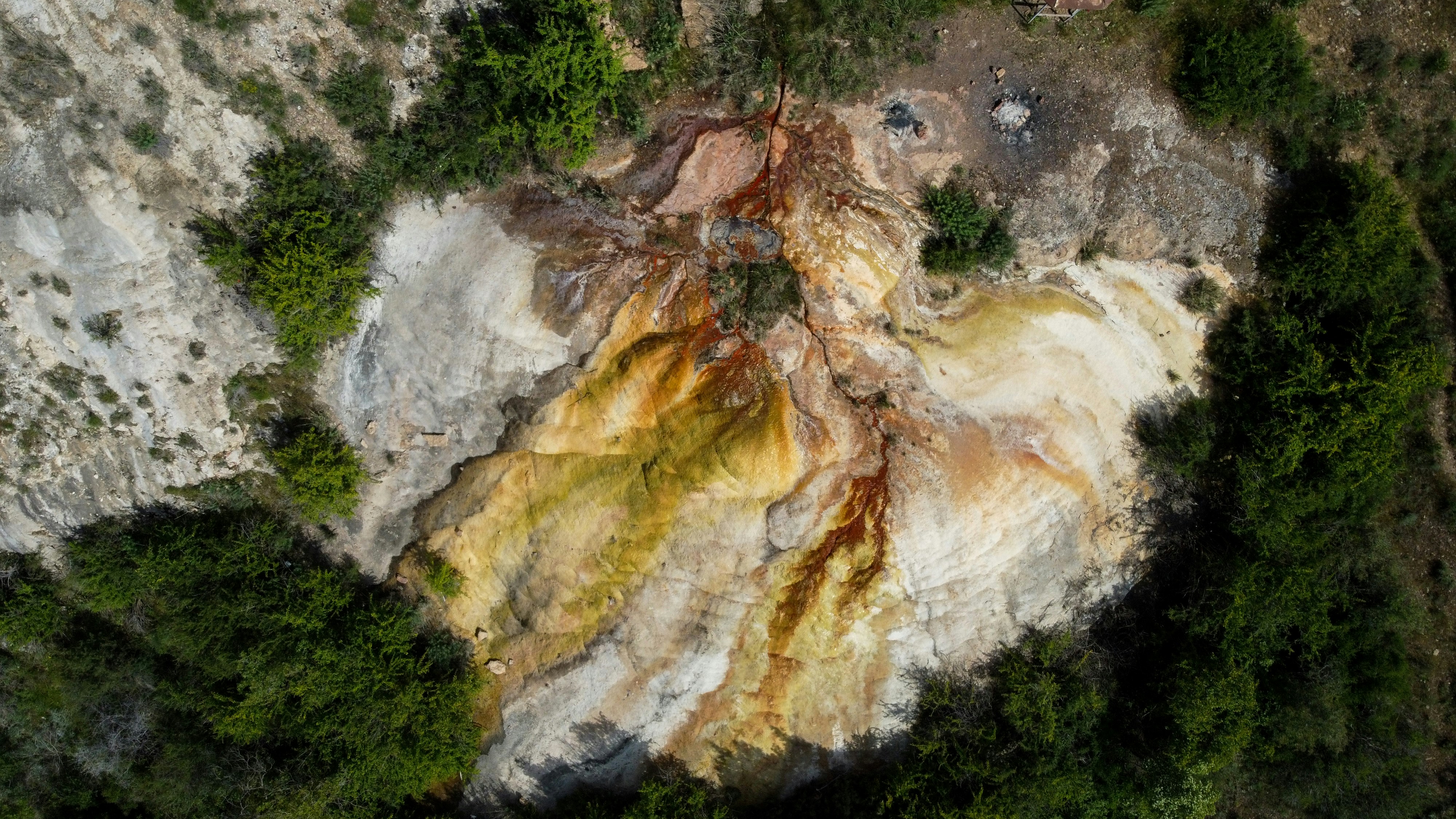 Colorful mineral terrace carved through rugged hillside