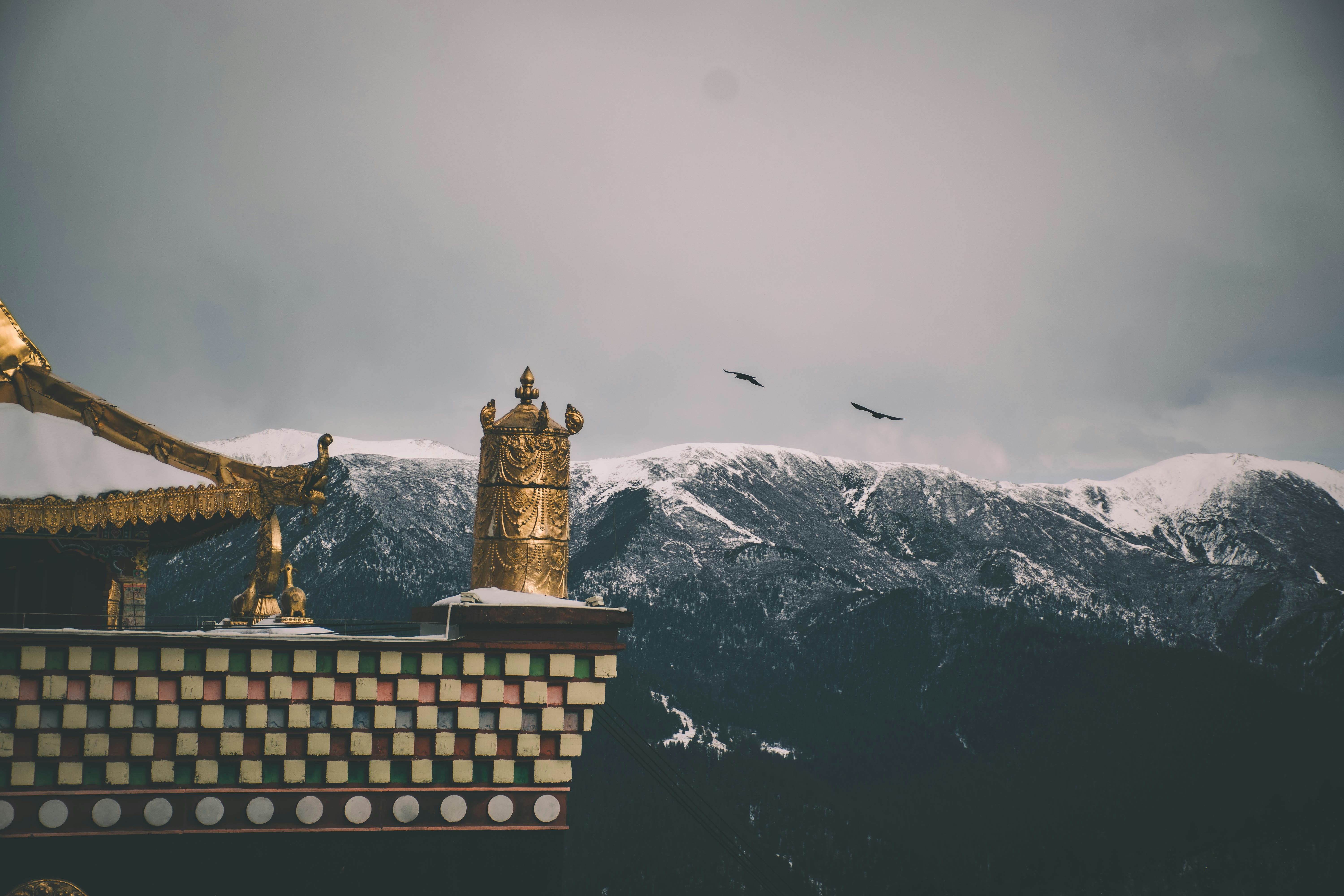Temple Rooftop with Mountain Backdrop and Soaring Birds