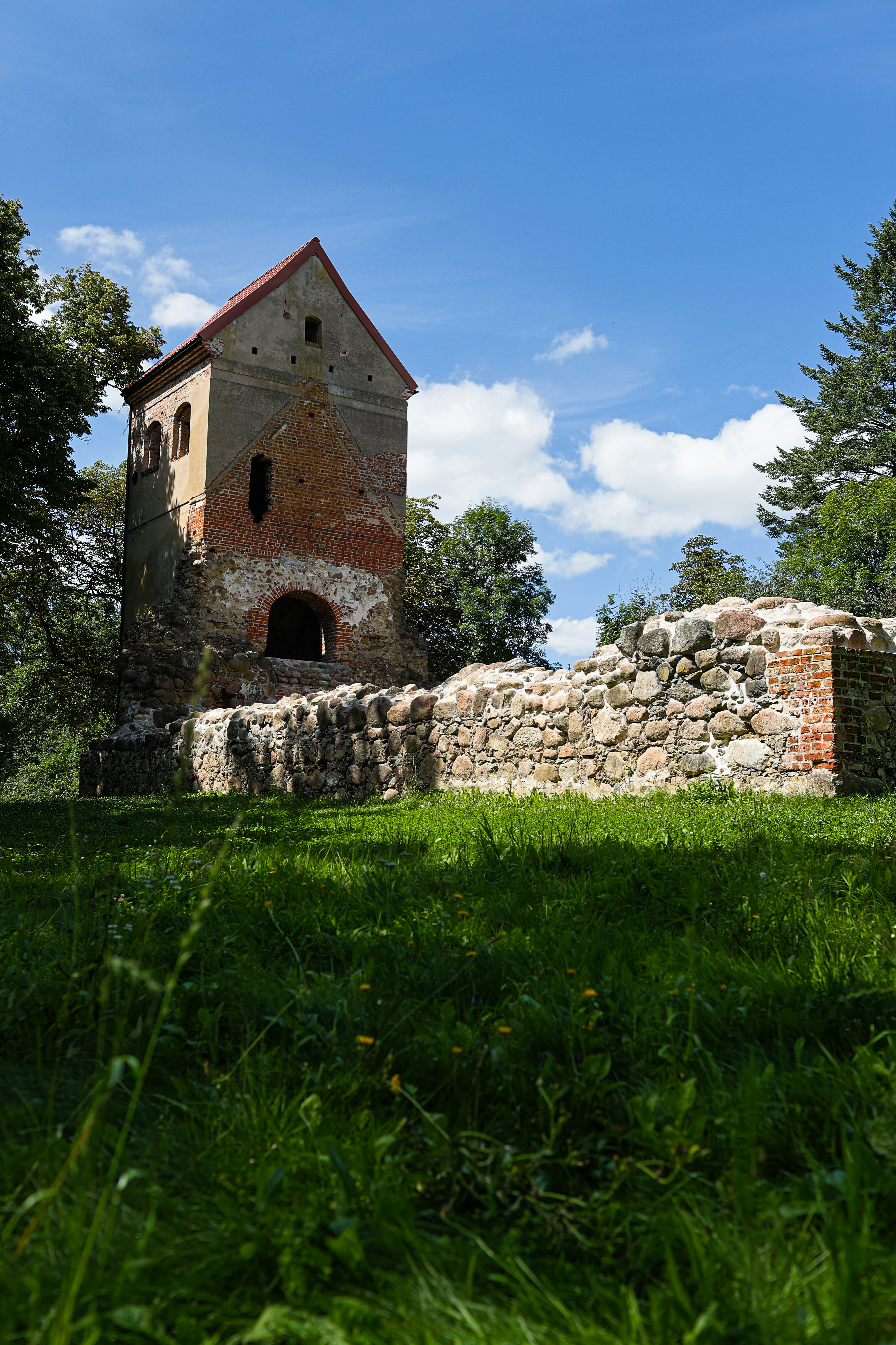 Ruins alongside sunlit meadow under a bright sky