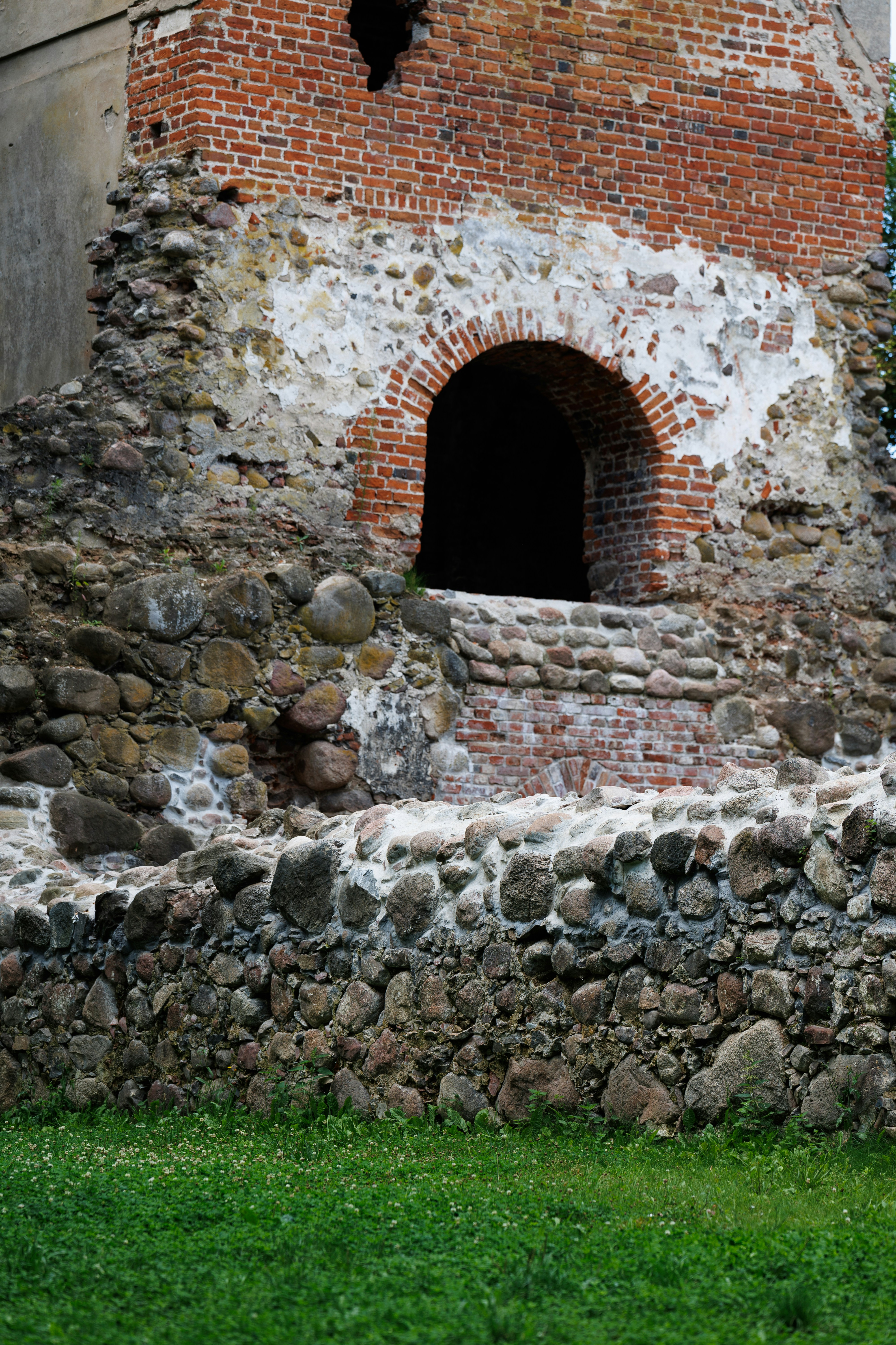 Stone Arch and Brick Chimney: A Weathered Fortress Reclaiming its Garden