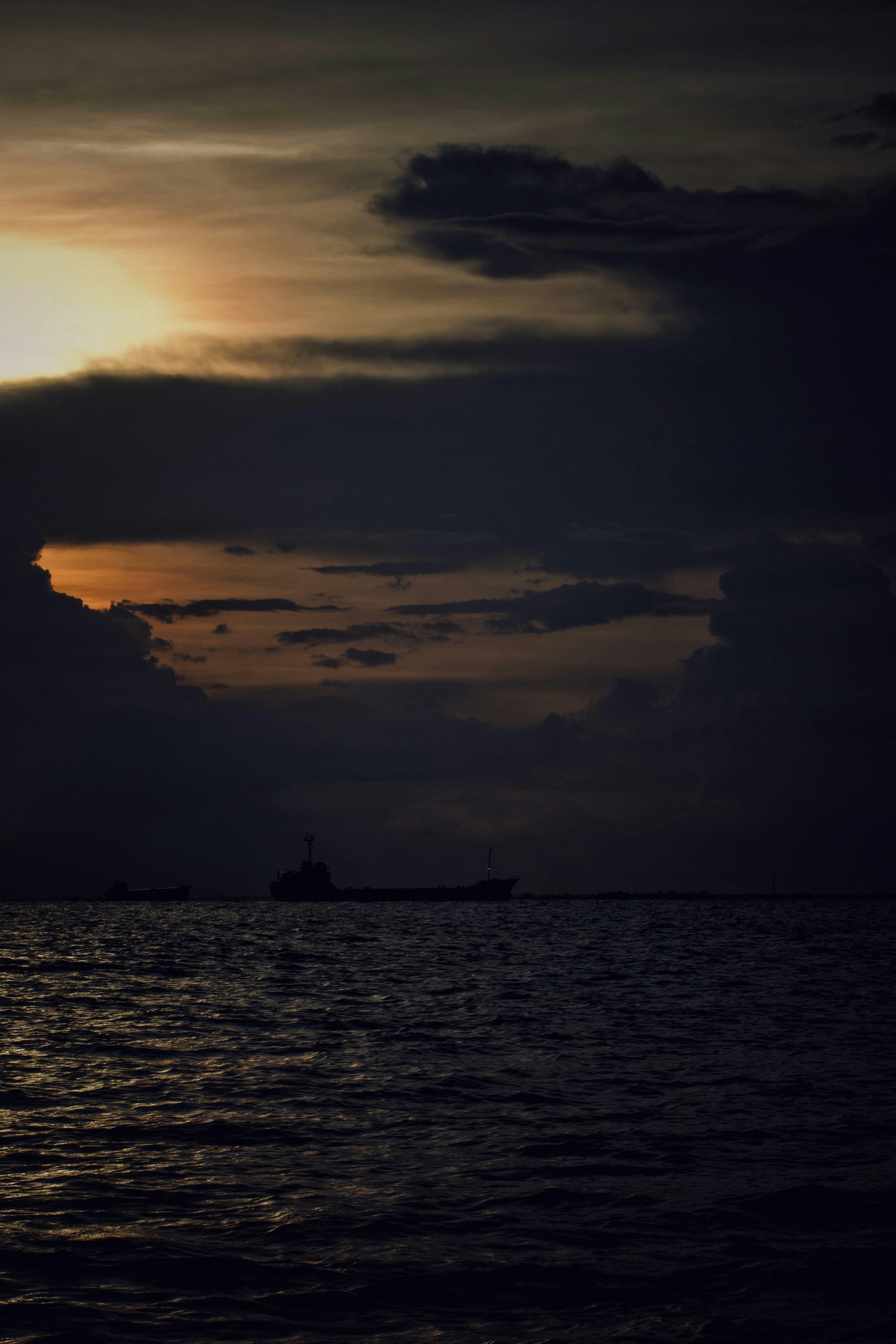 Quiet Horizon: A Sunlit Vessel Silhouette on a Dusk-Textured Sea