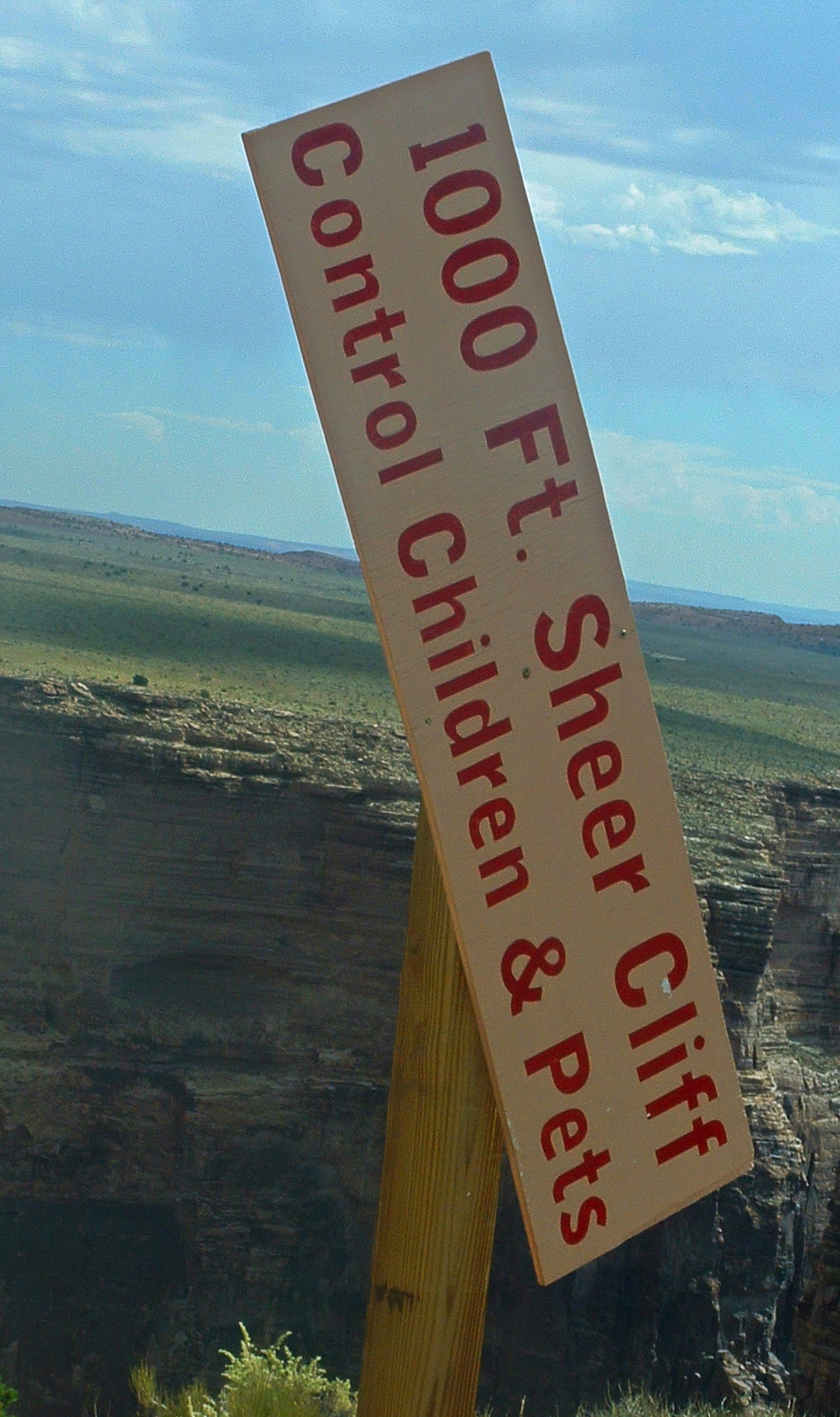 Tilted Signpost: 1000 ft. Sheer Cliffs and a Warning in the Open Plain