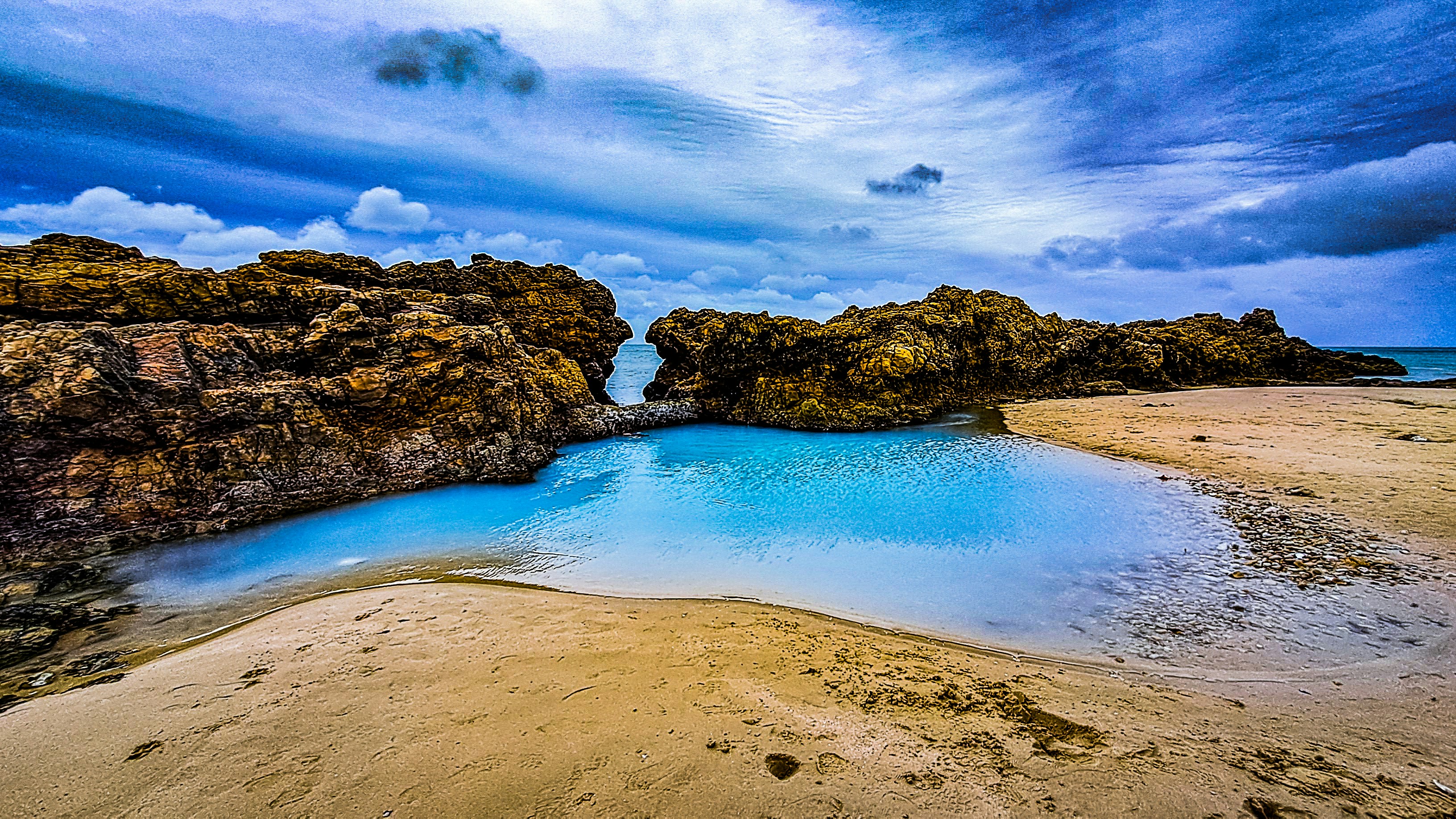 Tide Pool Between Weathered Cliffs Under A Cerulean Sky
