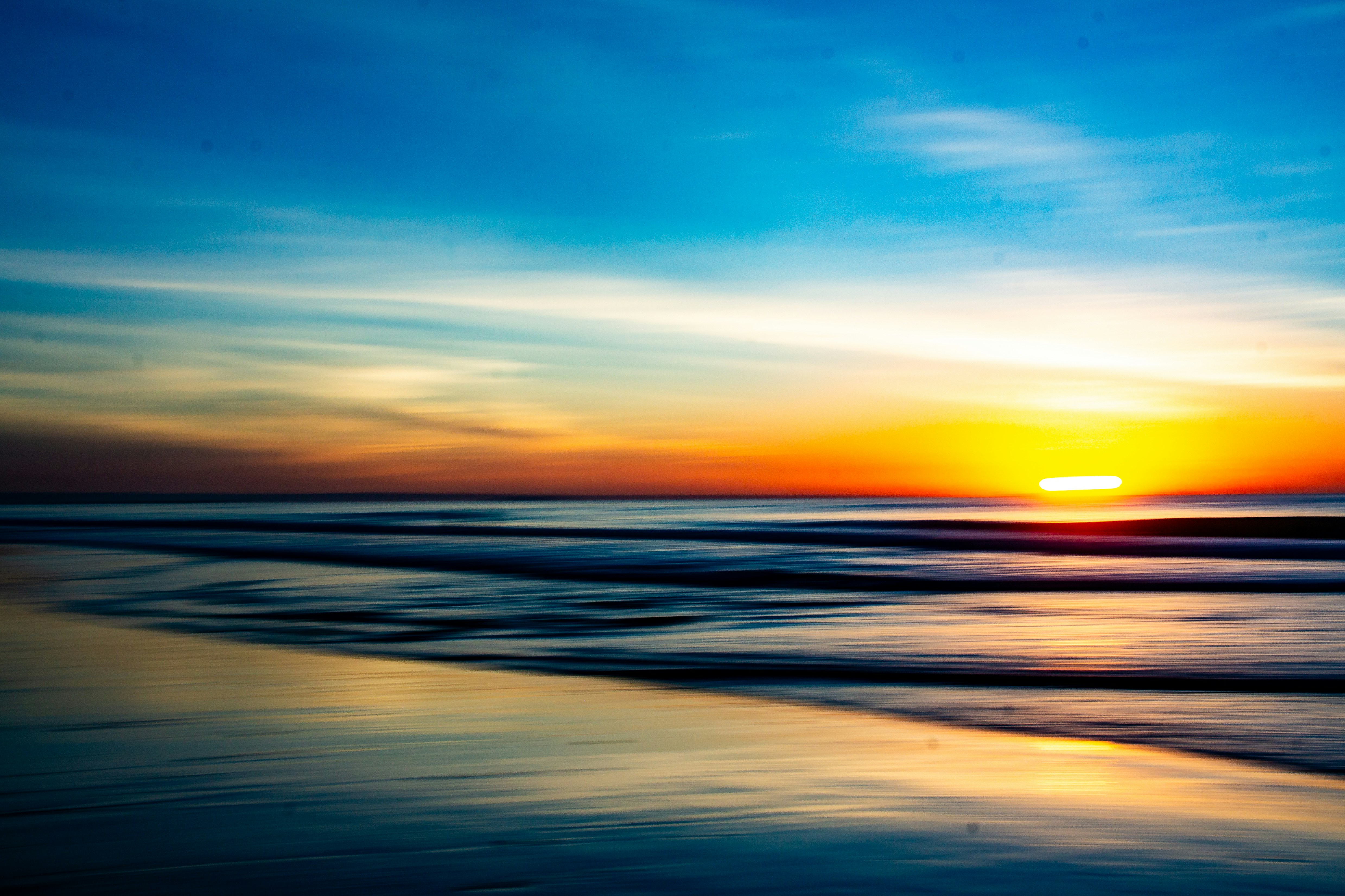 Sunset on Quiet Tides: Ribboned Waves and Looming Horizon