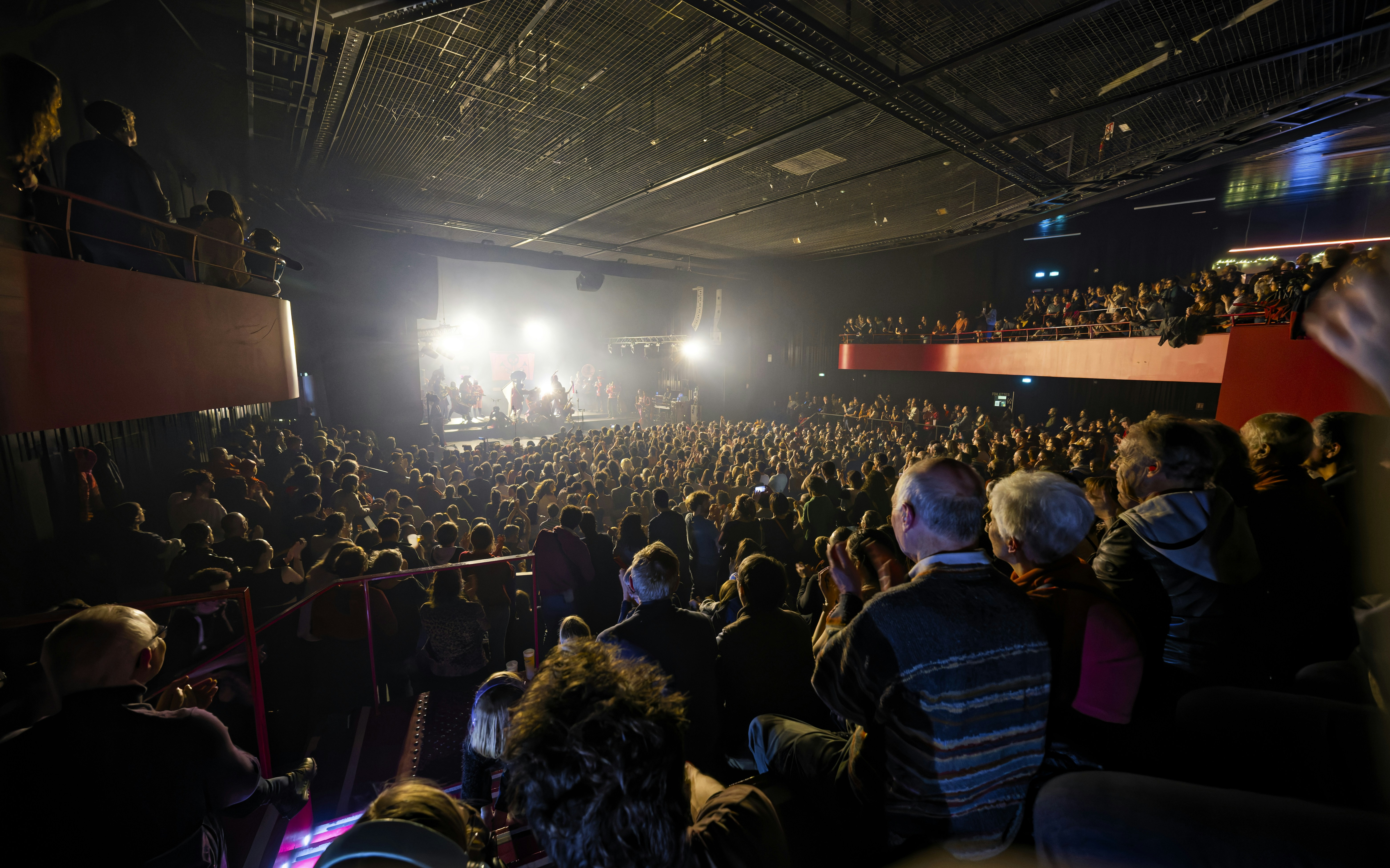 Center Stage: Crowd Faces the Spotlight in a Dim Concert Hall