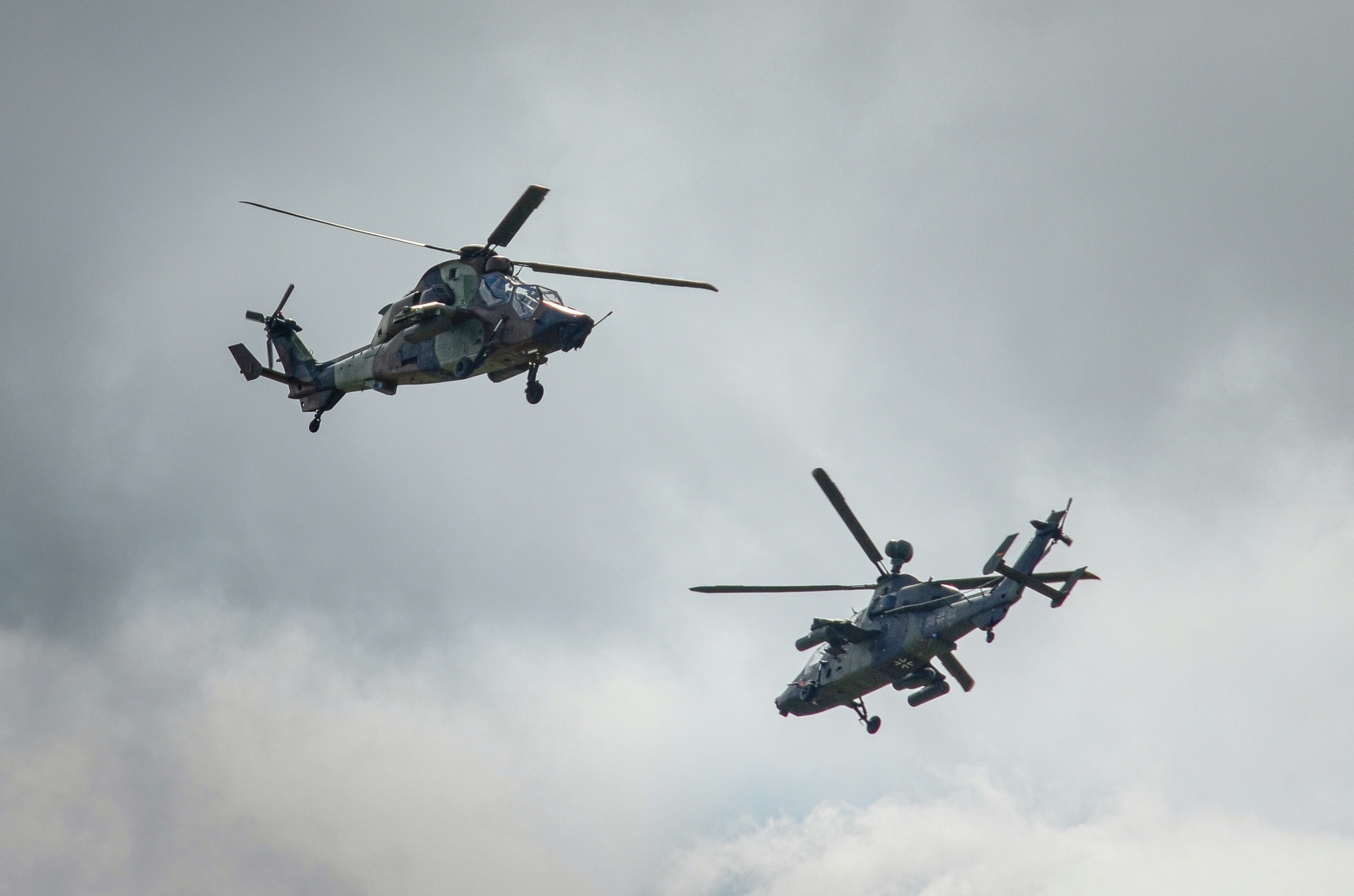 Twin-Helix Flight: Two military helicopters carving through overcast skies