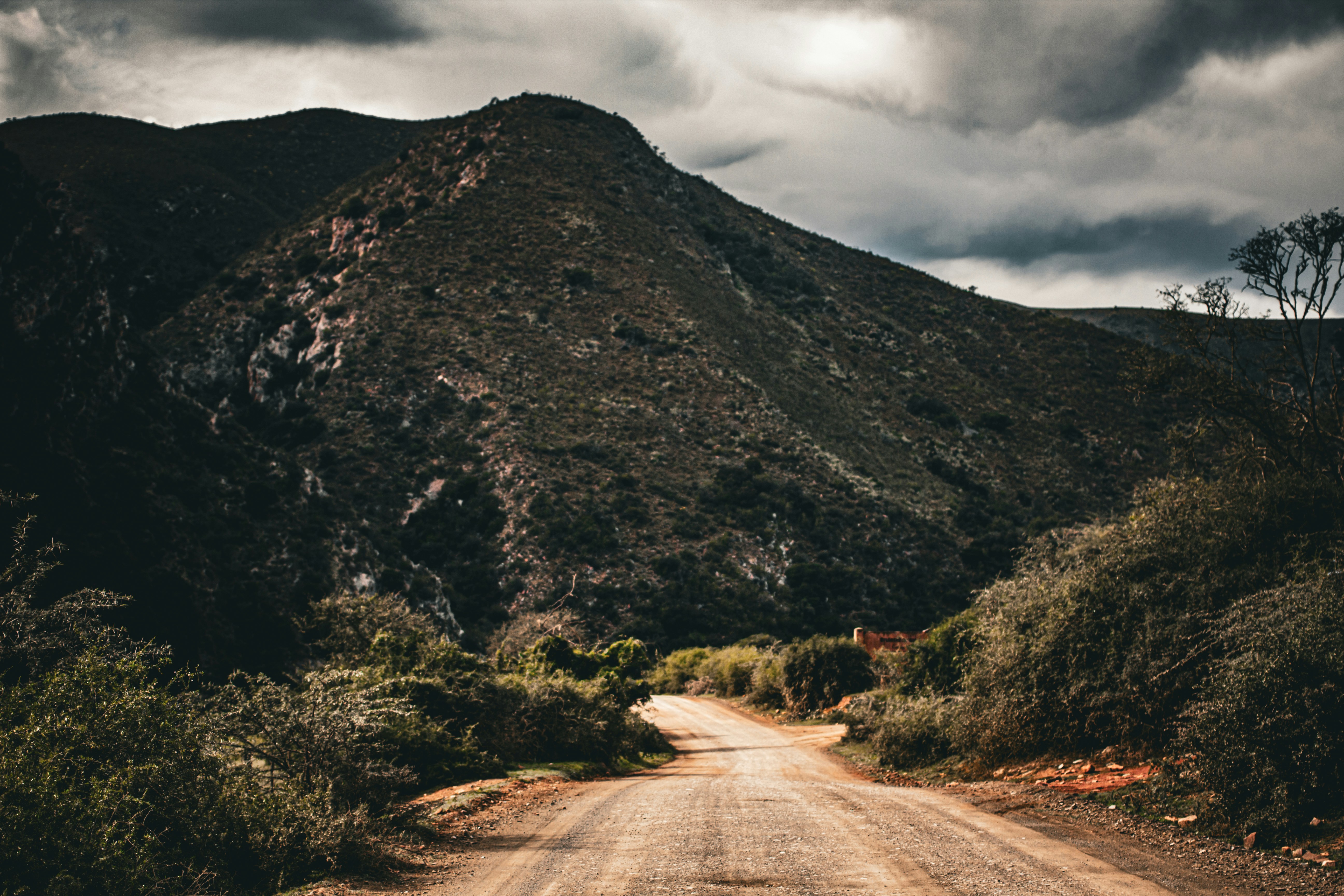 Dusty Mountain Road vanishing toward stormy skies