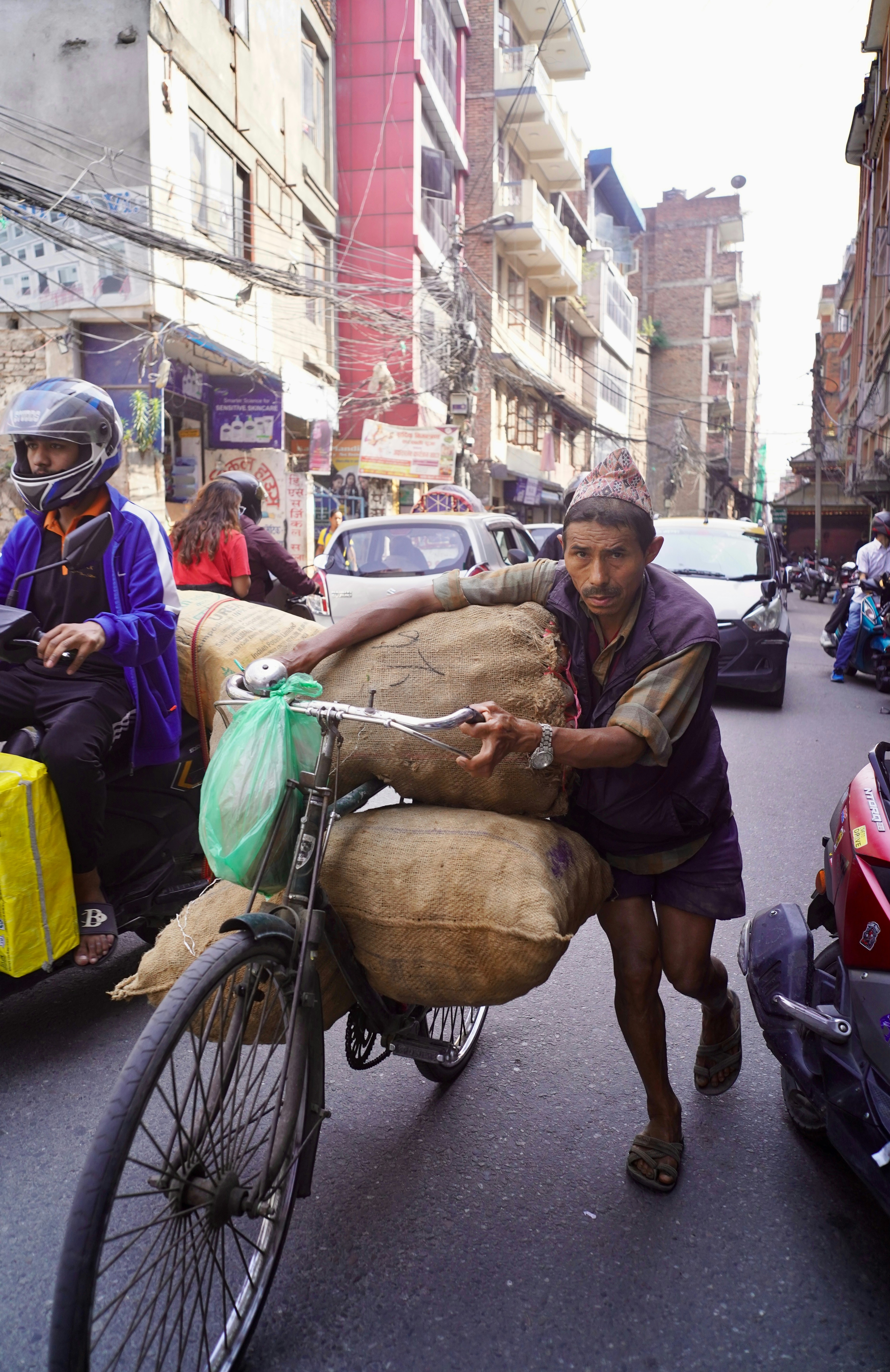 Cyclist with a heavy load navigates a crowded urban street