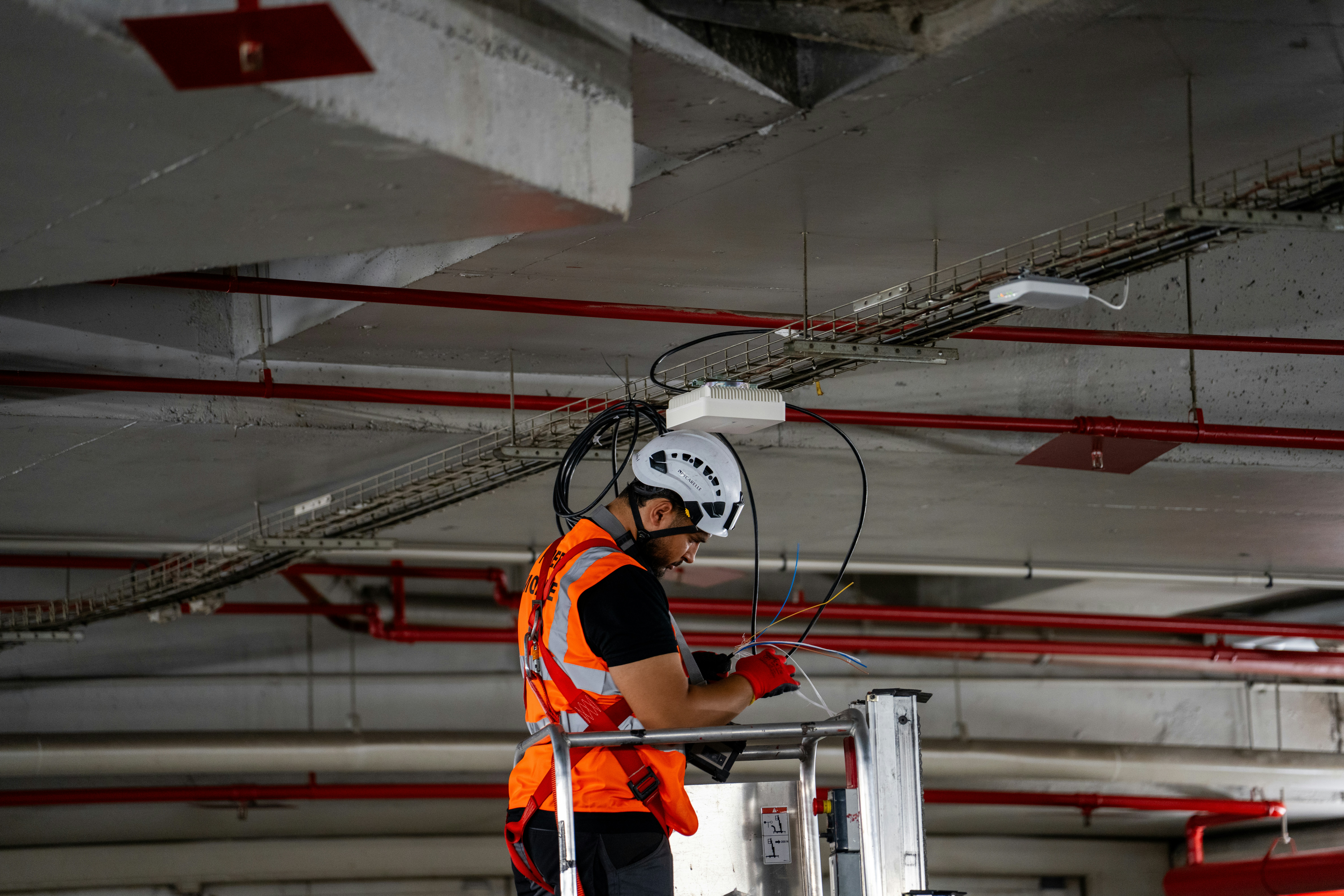 Electrical worker in a harness inspecting cables on a suspended platform