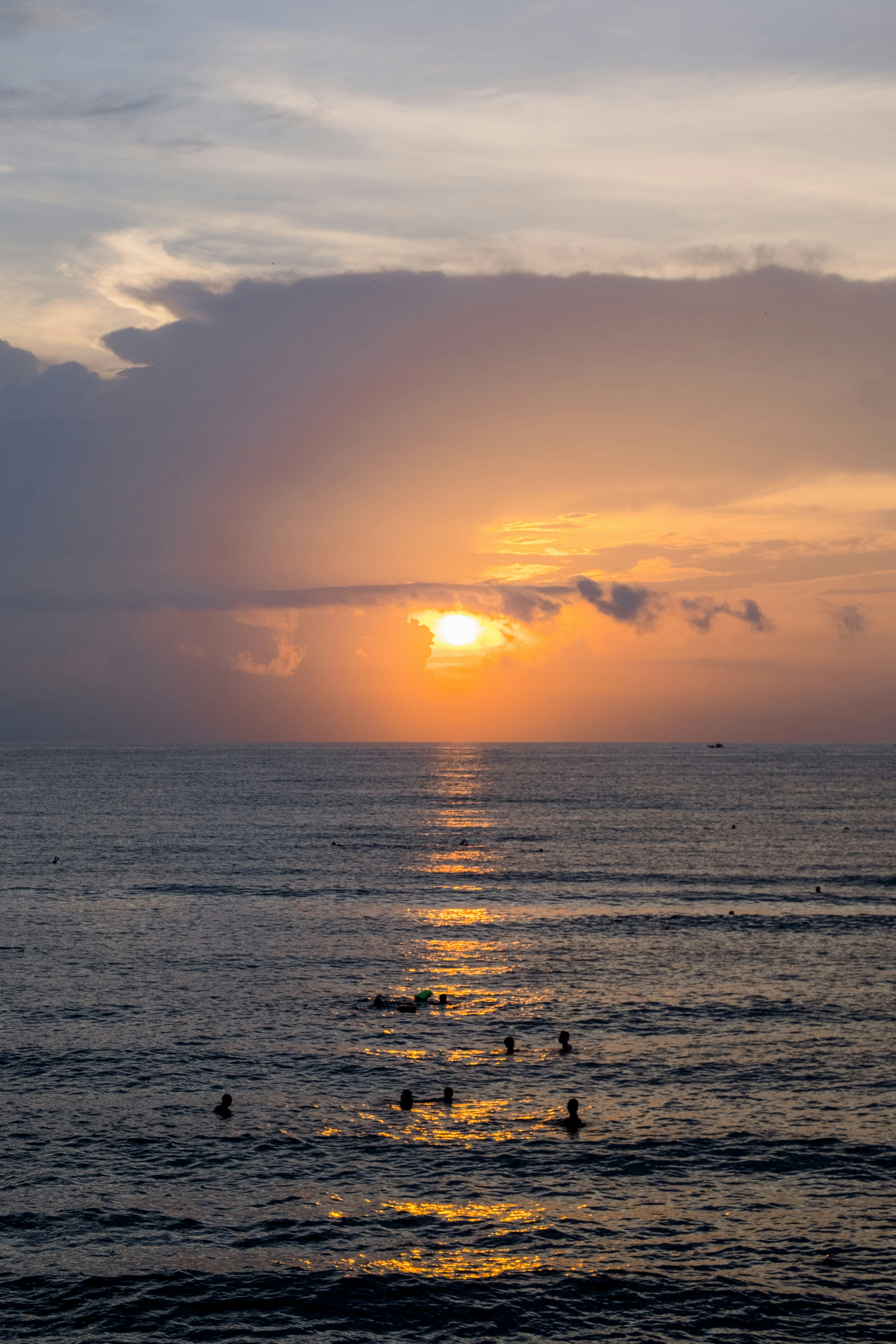 Silhouetted surfers in the ocean during a beautiful sunset.