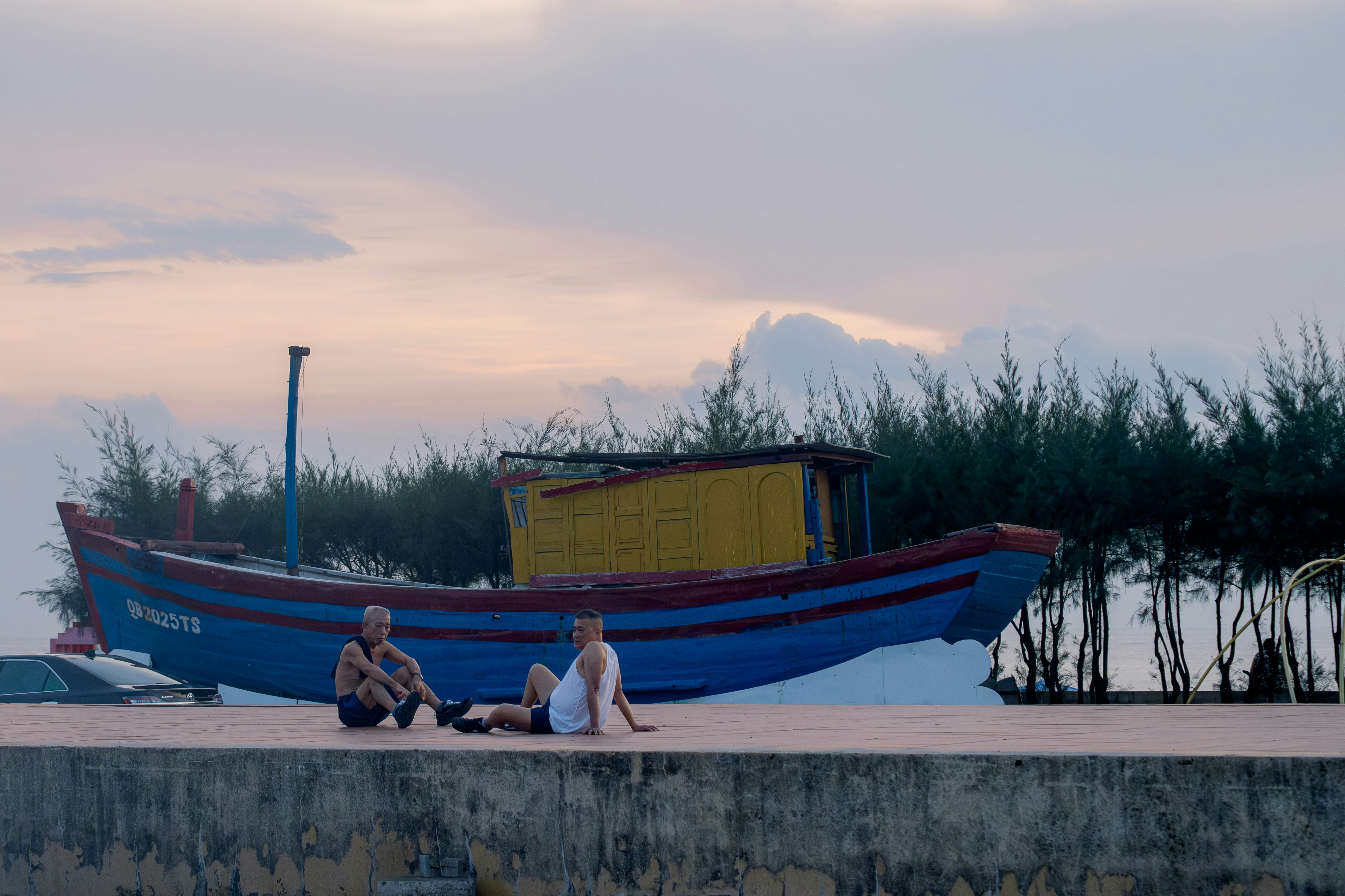 Quiet Dockside: A Blue Boat and Two Figures in Evening Light