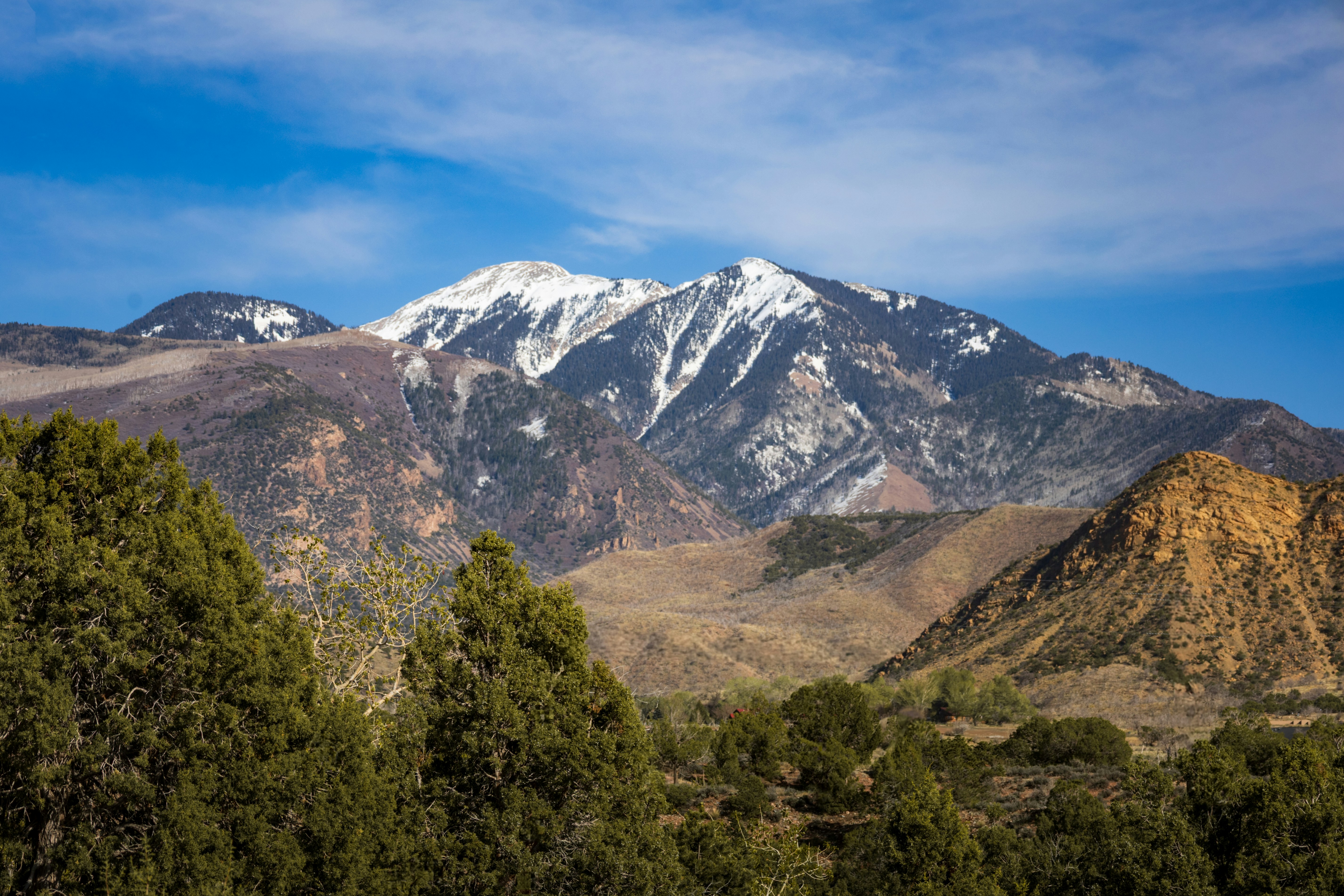 Snow-dusted peaks framed by arid foothills under a cobalt sky