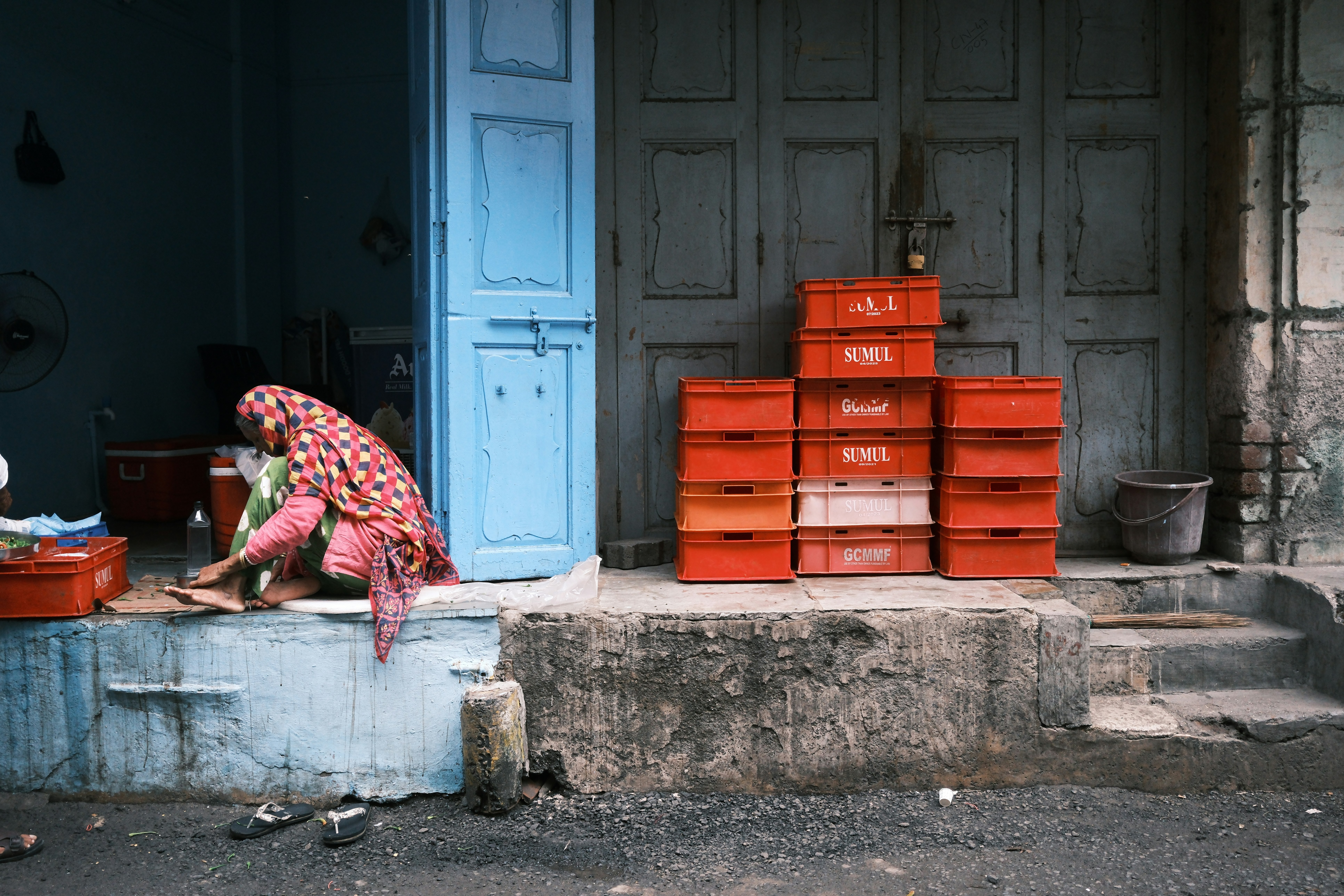 Red crates by the doorway: a lone worker at the edge of a quiet street