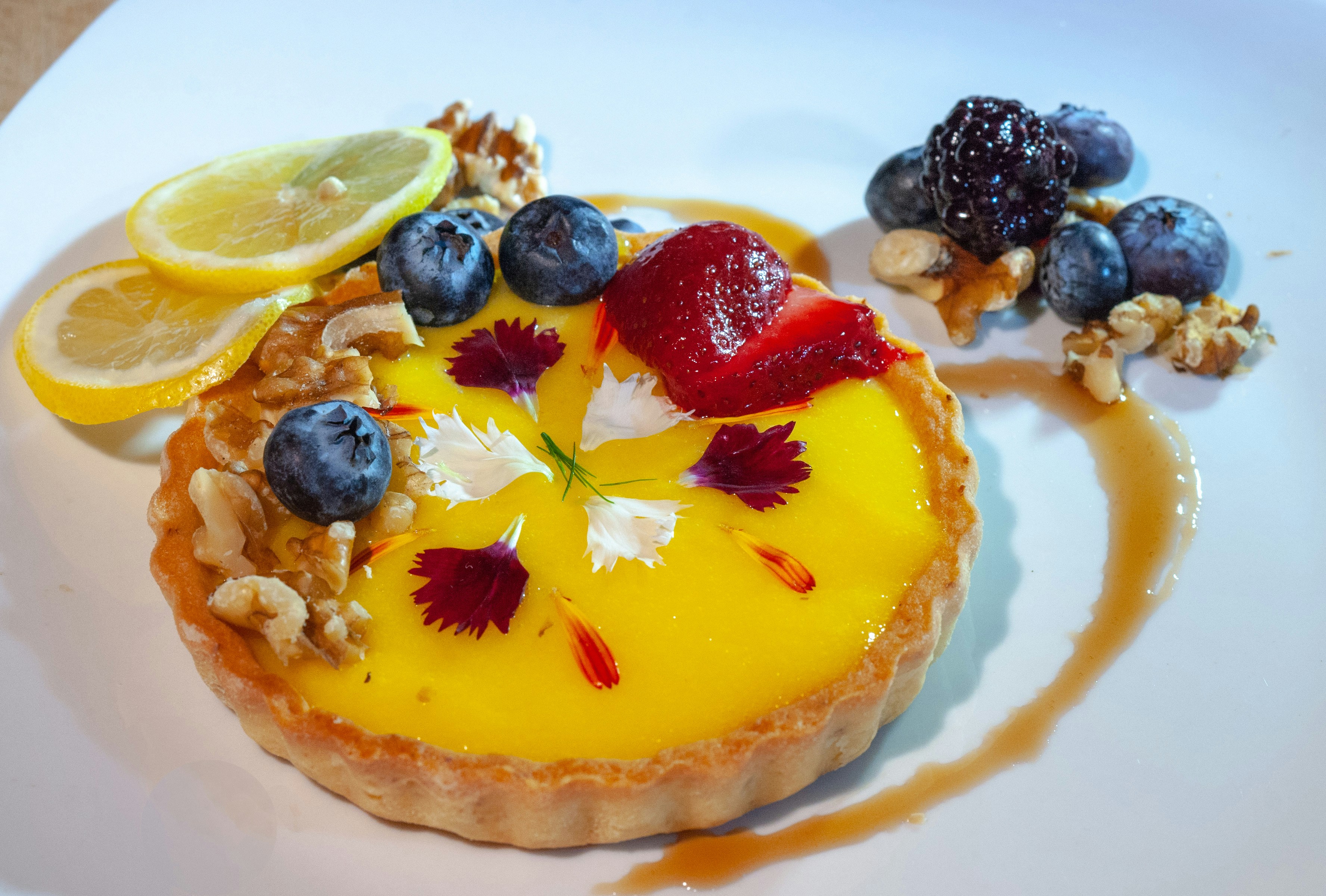 Golden Mango Custard Tart with Mixed Berries and Floral Accents