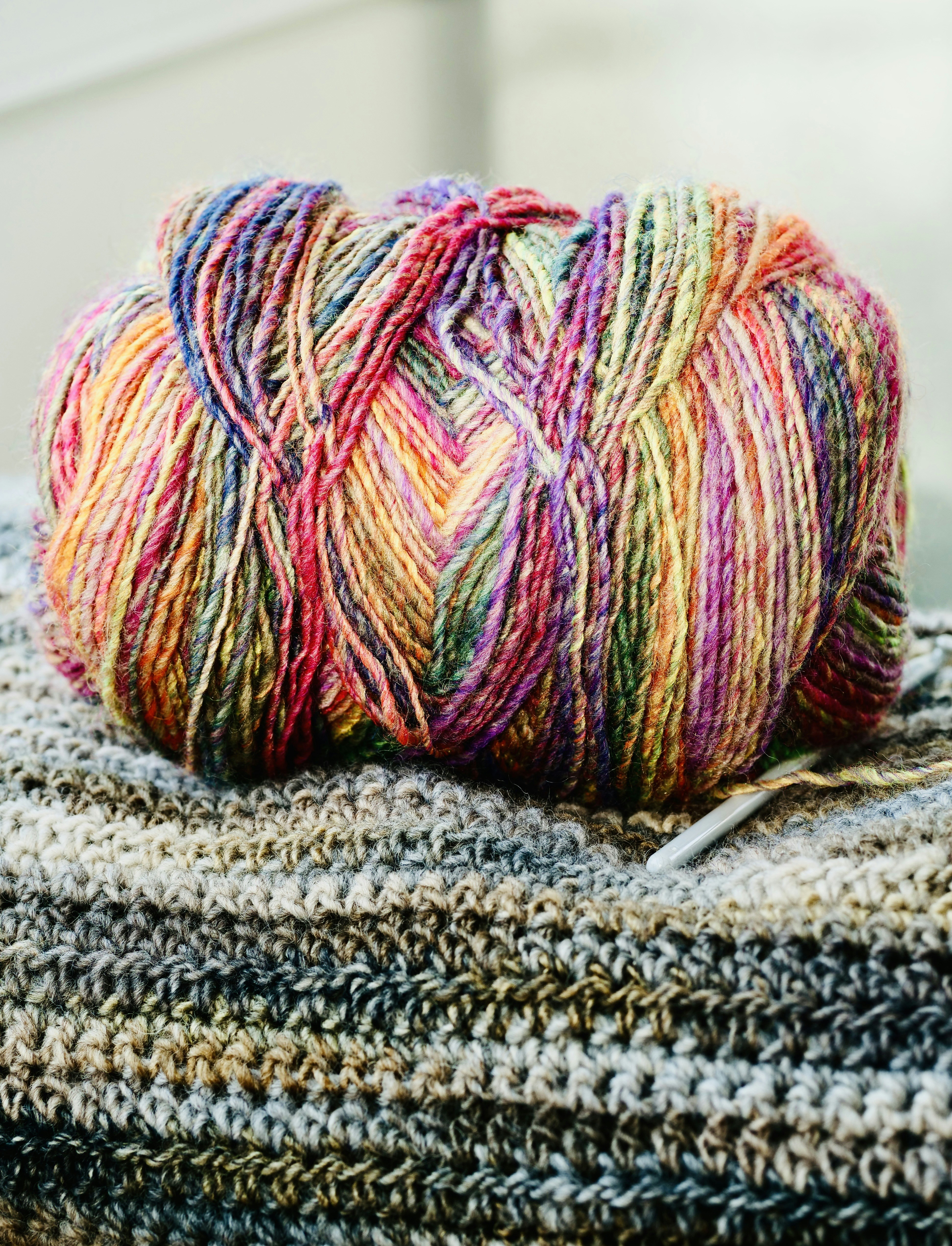Rainbow Yarn Ball resting on a textured knitted surface