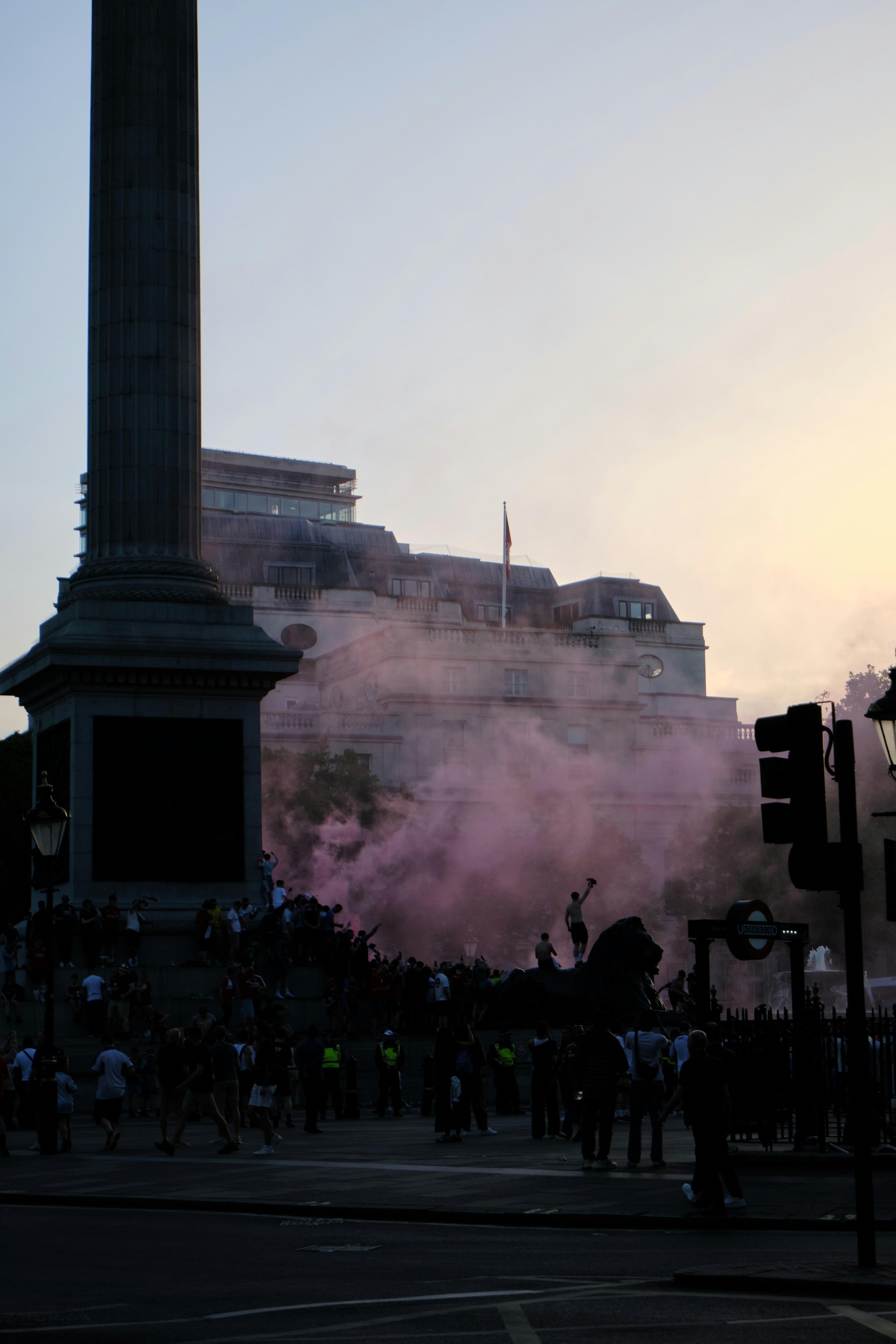 Silhouetted crowd and plume at a grand monument during dusk