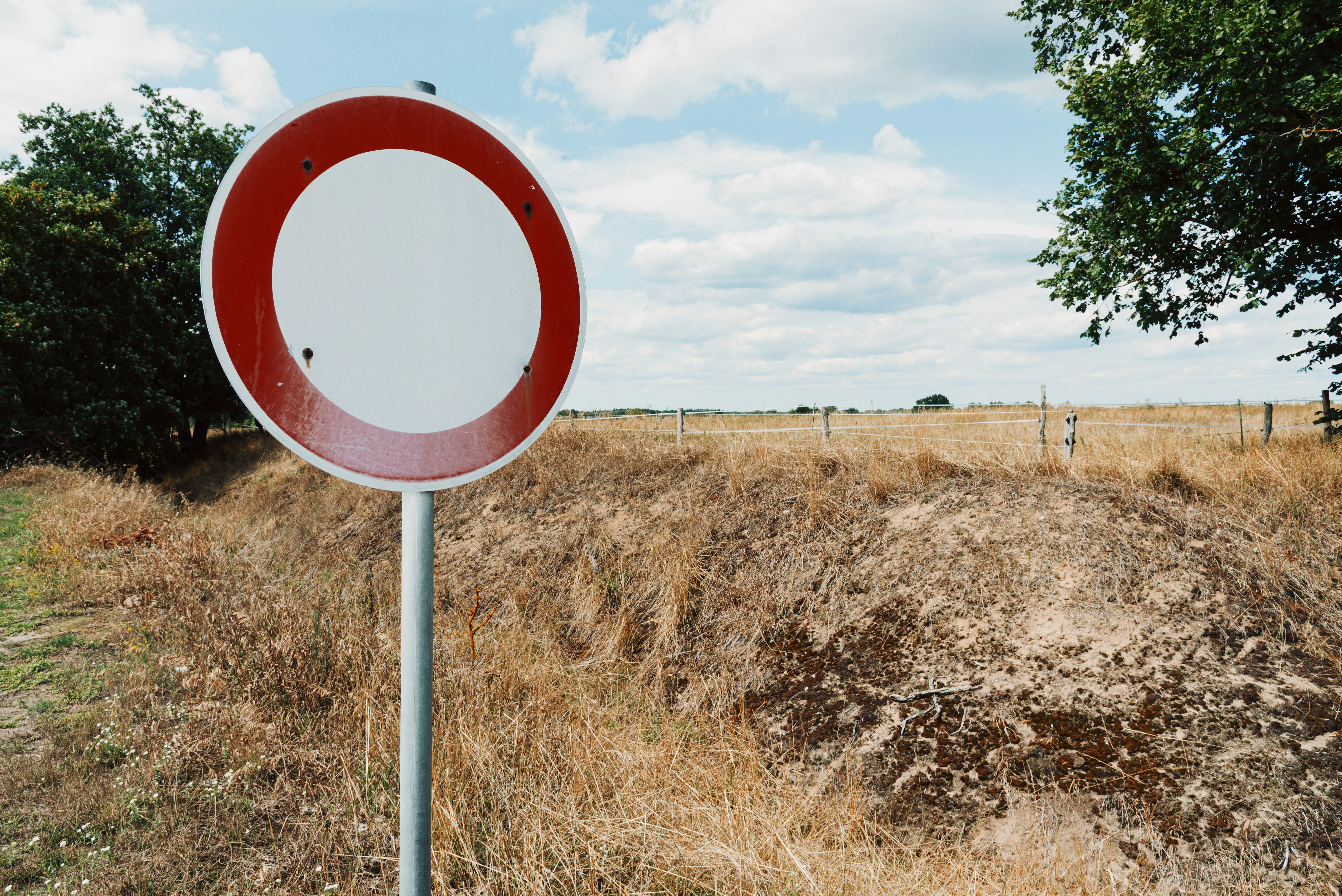Dusty Field Gatekeeper: A Weathered No-Entry Sign Oversees Silent Plains