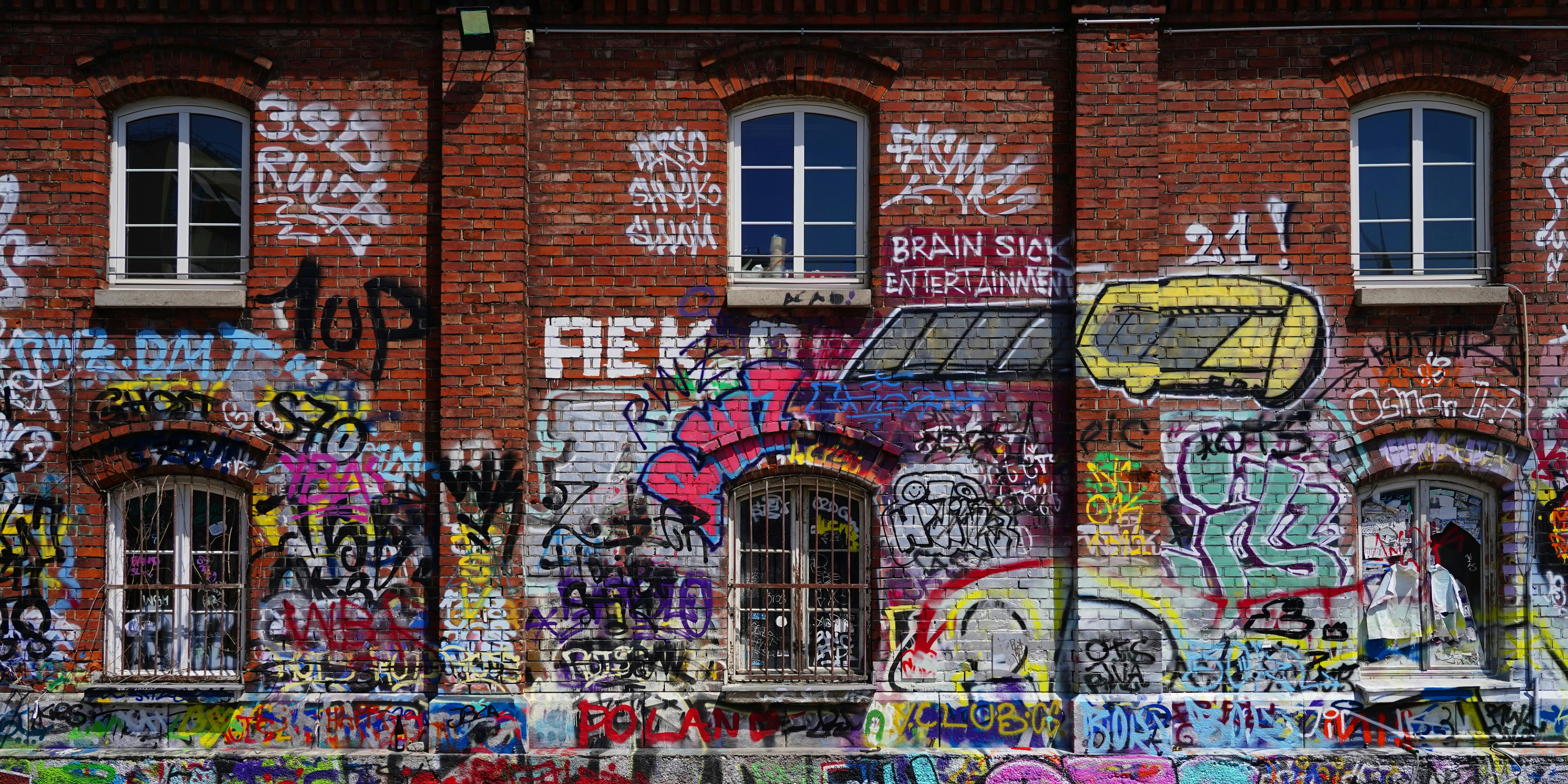 Brick Canvas: Graffiti Chronicle Across a Red Facade