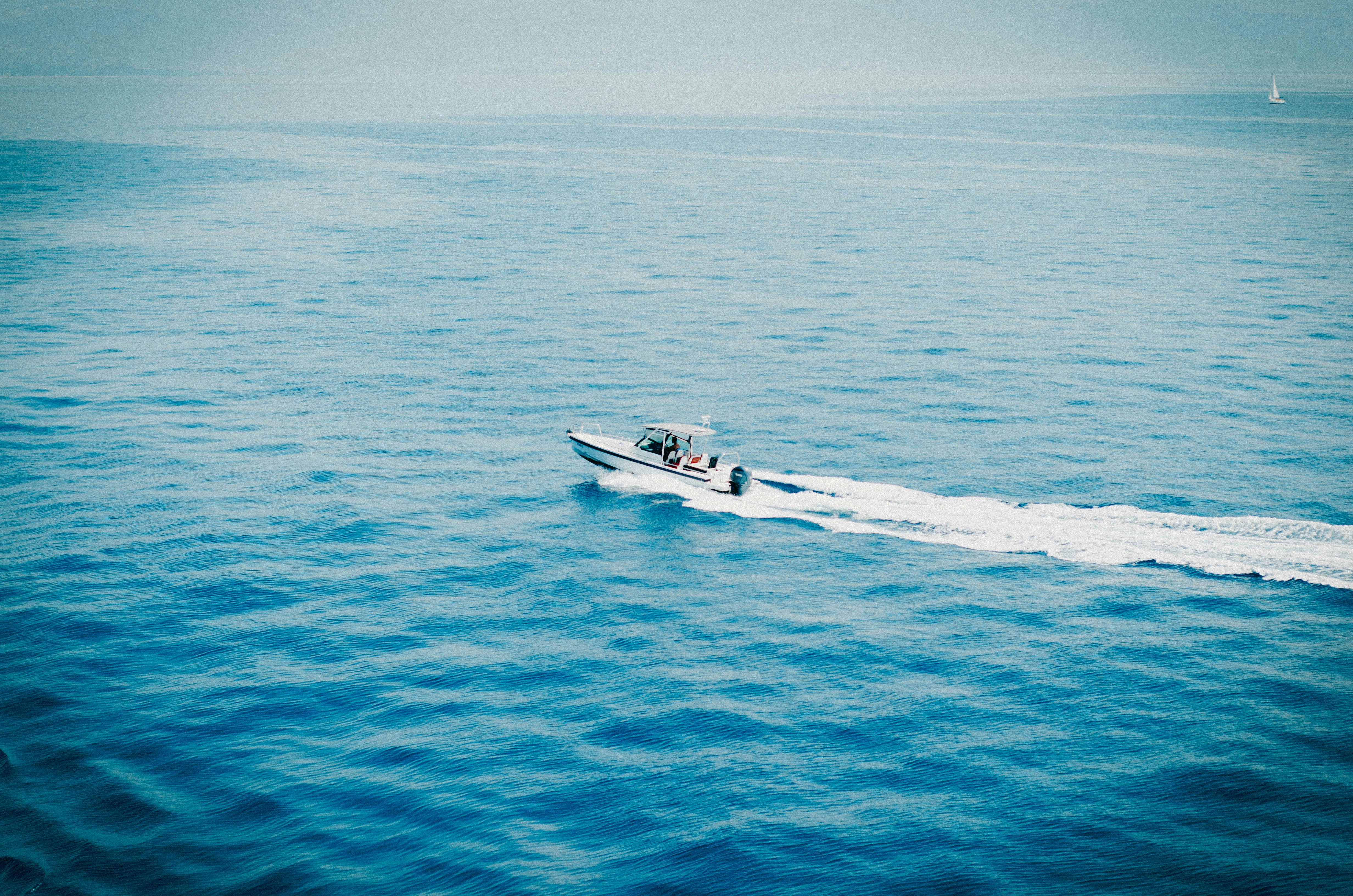 Azure Wake: A Lone Boat Carves Through Open Ocean