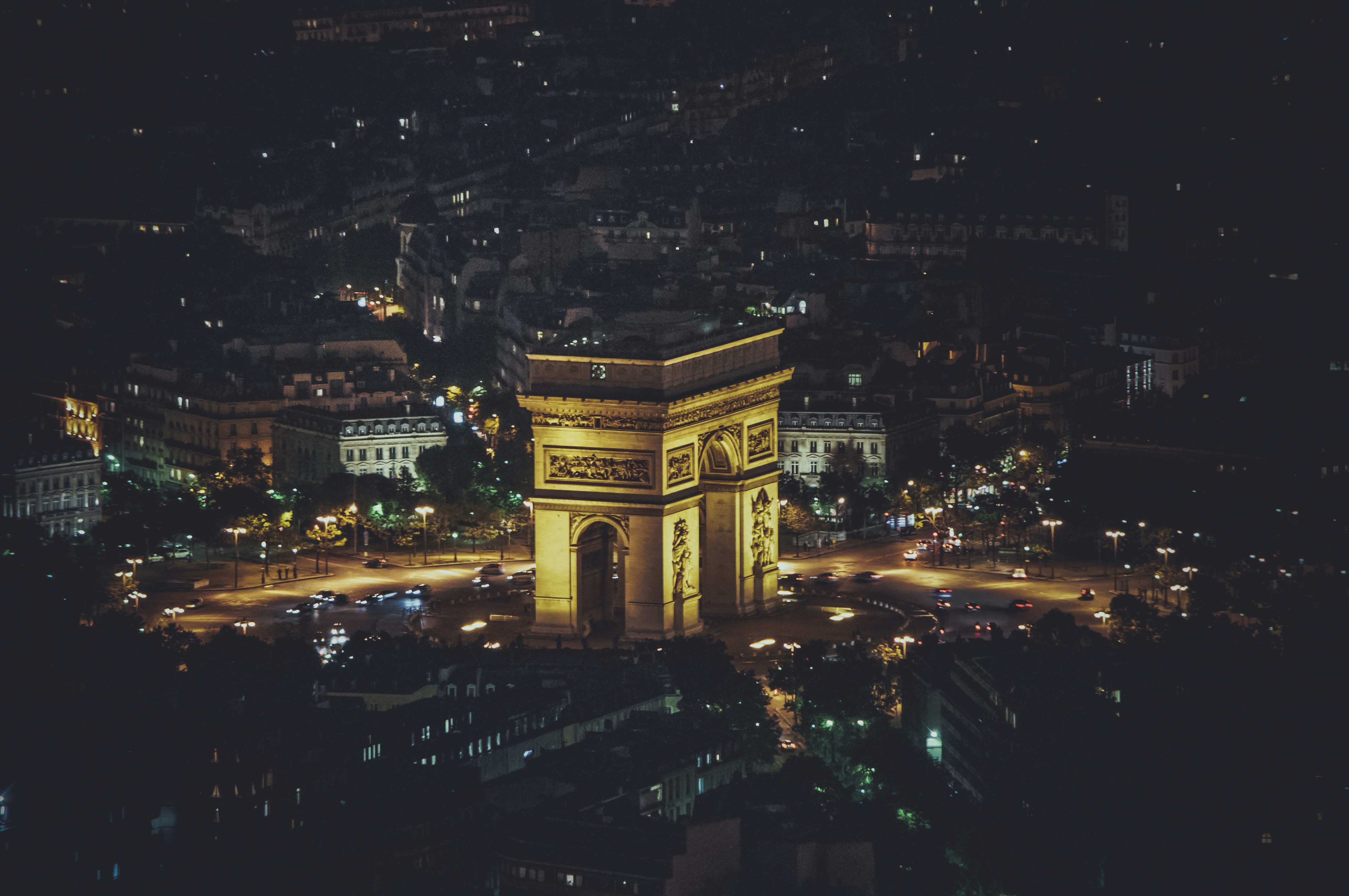 Paris View from Tour Eiffel: Arc de Triomphe and City by Night A spectacular nighttime view from the Eiffel Tower, capturing the glowing Arc de Triomphe illuminated at the center of the star-shaped roundabout, surrounded by the sparkling city lights of nocturnal Paris stretching into the horizon.